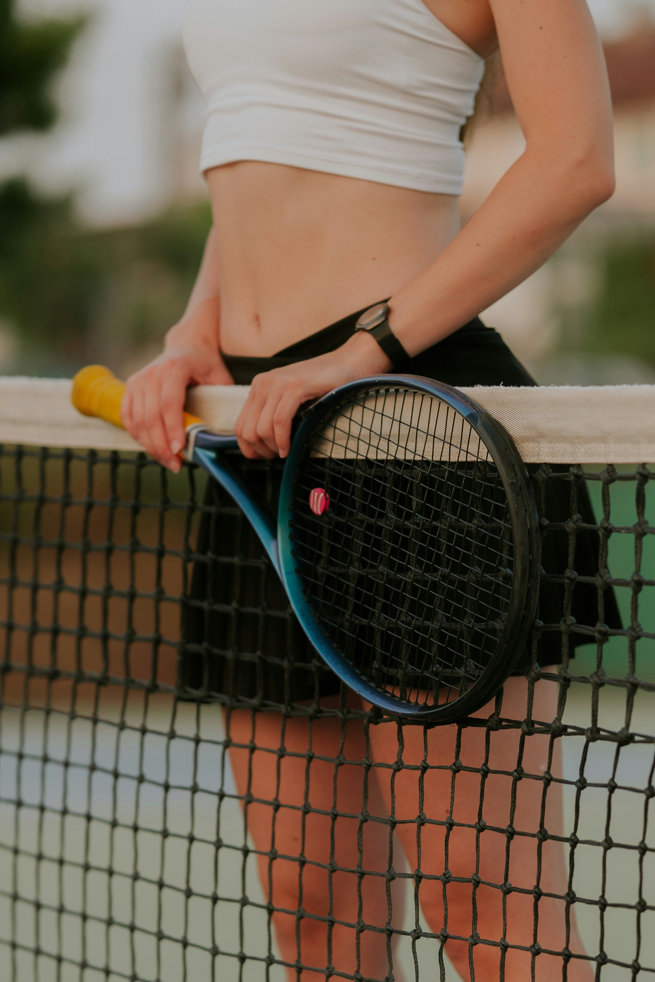 A tennis player holds a racket at the net.