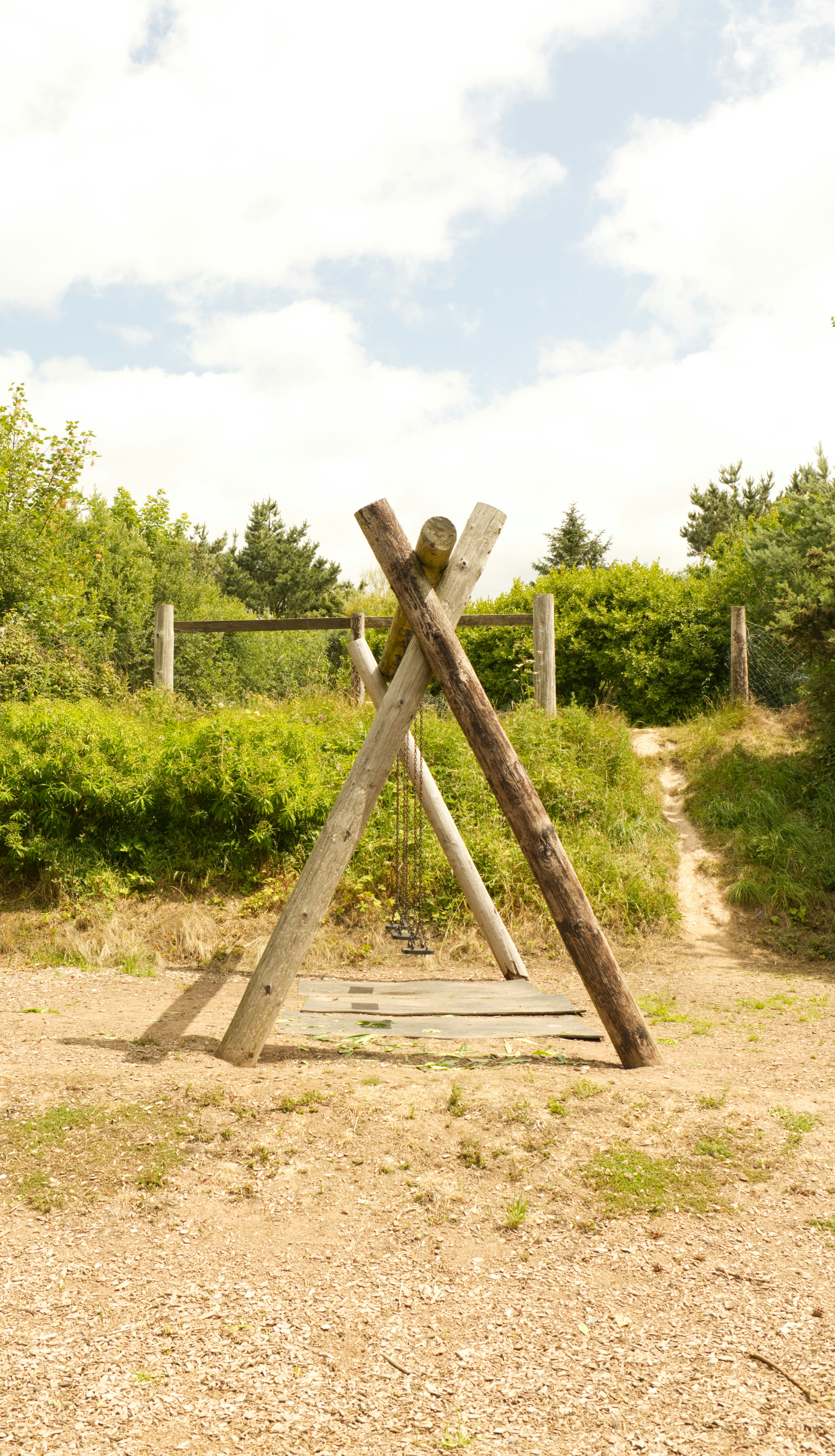 A wooden swing set in a natural setting.