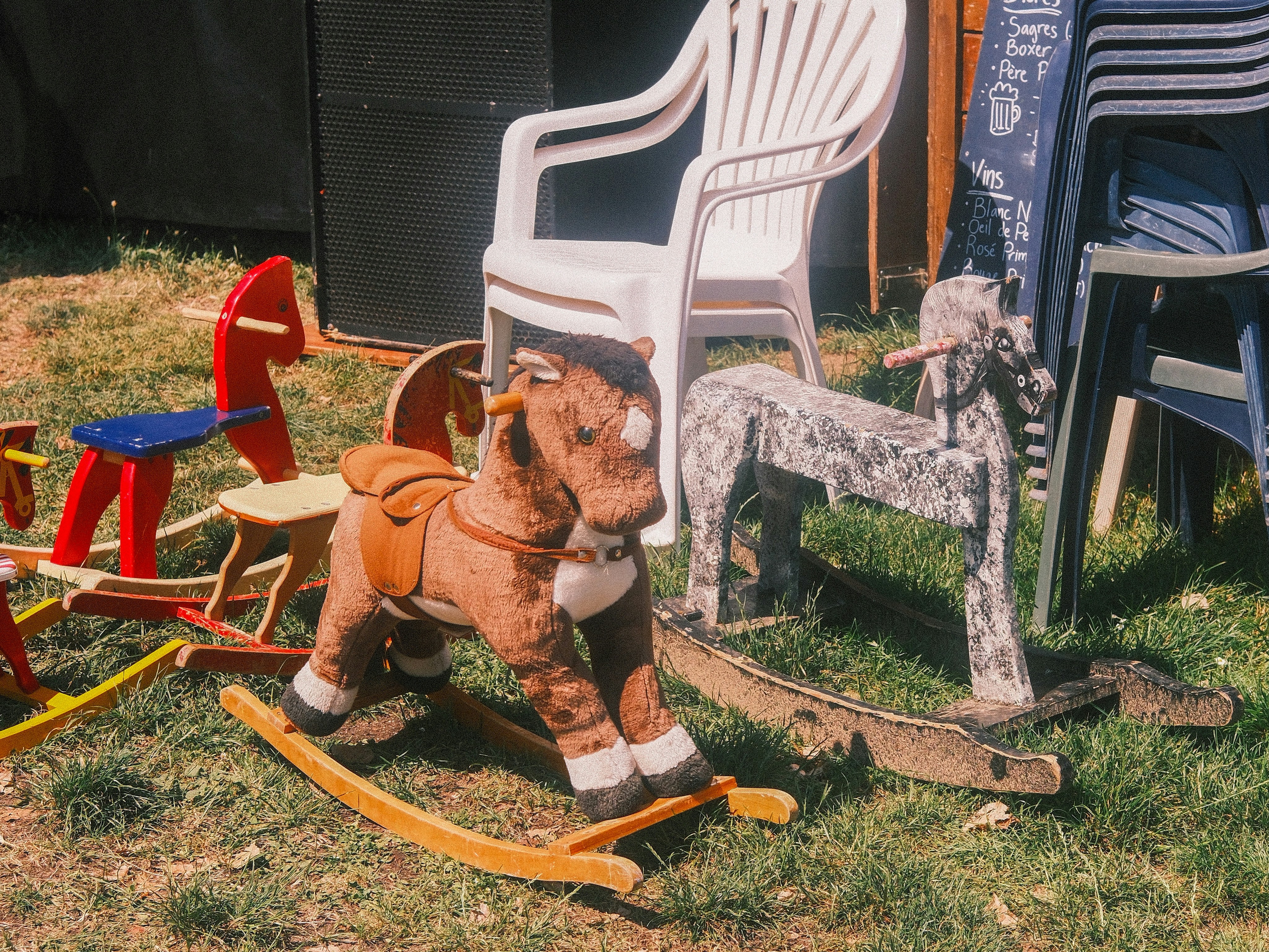 horseplay. | Many rocking horses are displayed outside on grass.