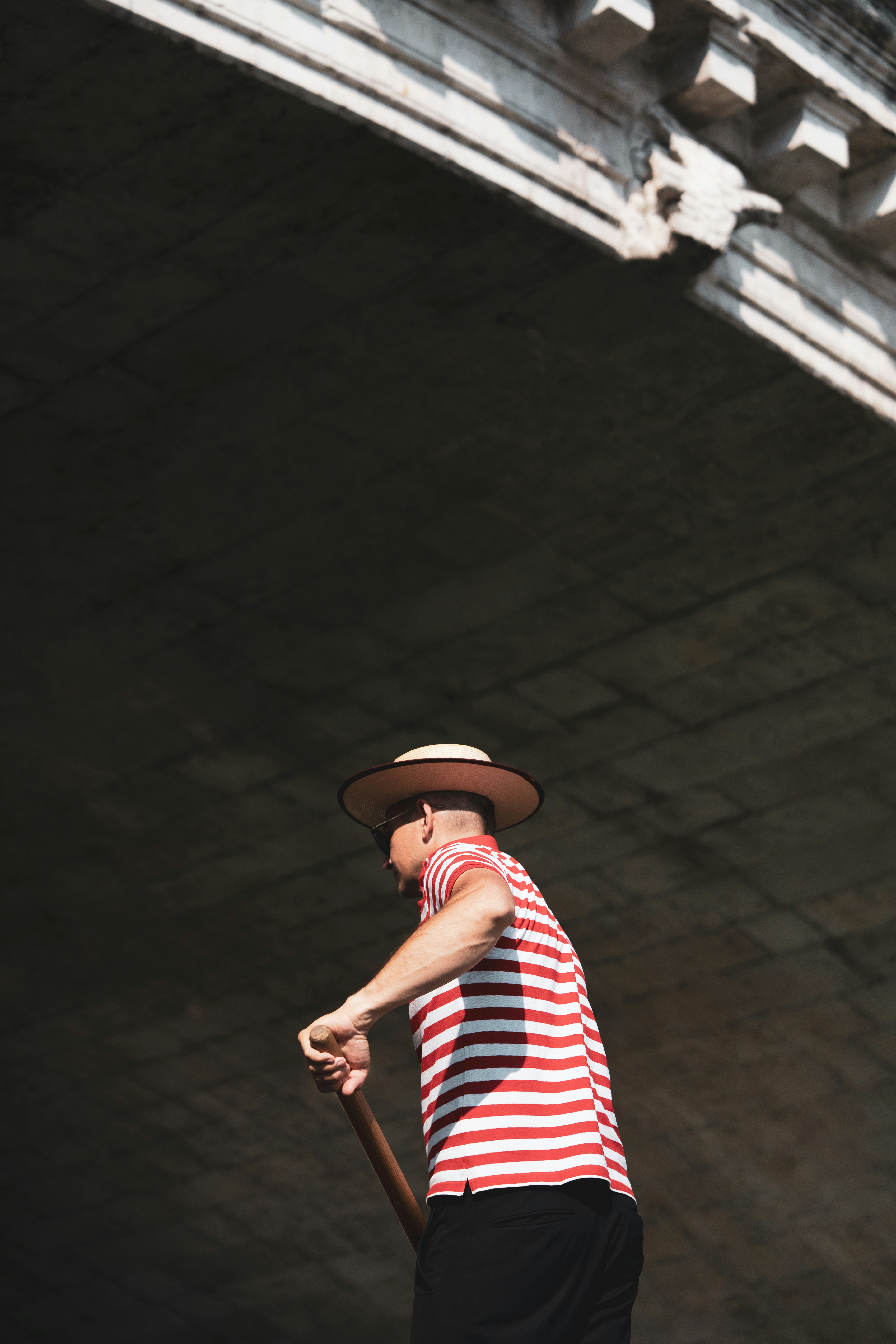 A gondolier paddles beneath a stone bridge.