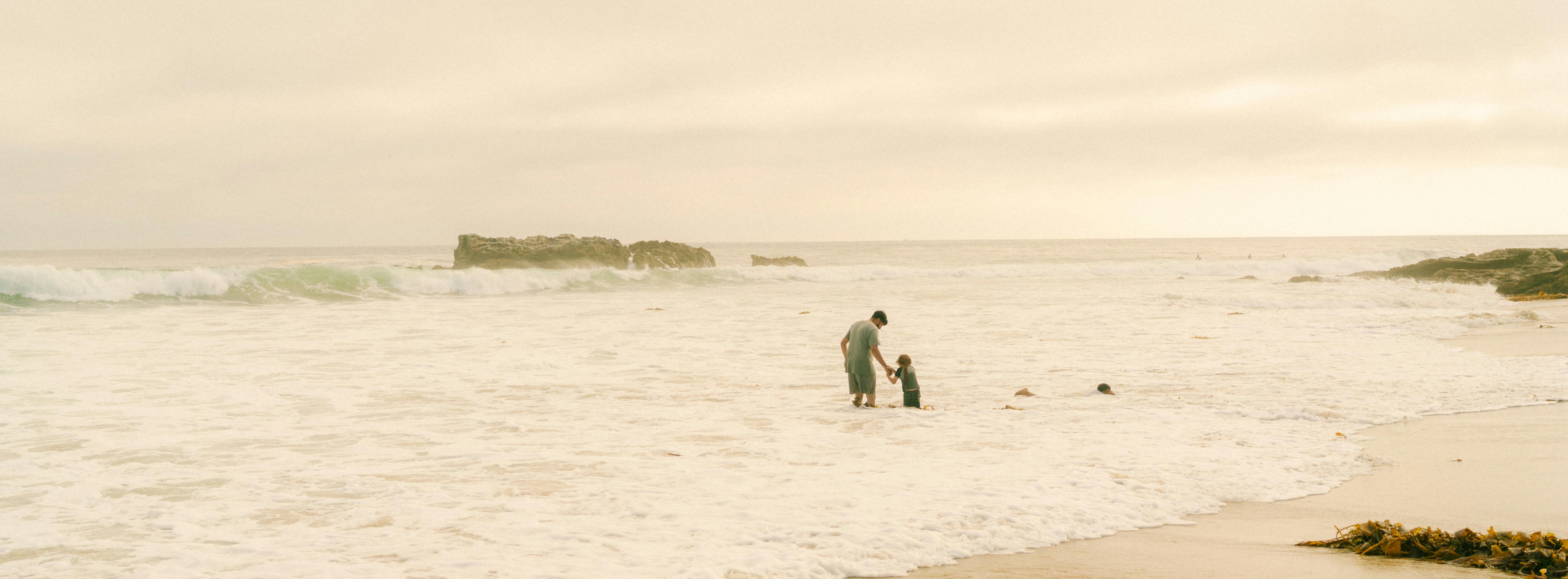 Gentle Shoreline Moment: A Father and Child Beneath Quiet Skies