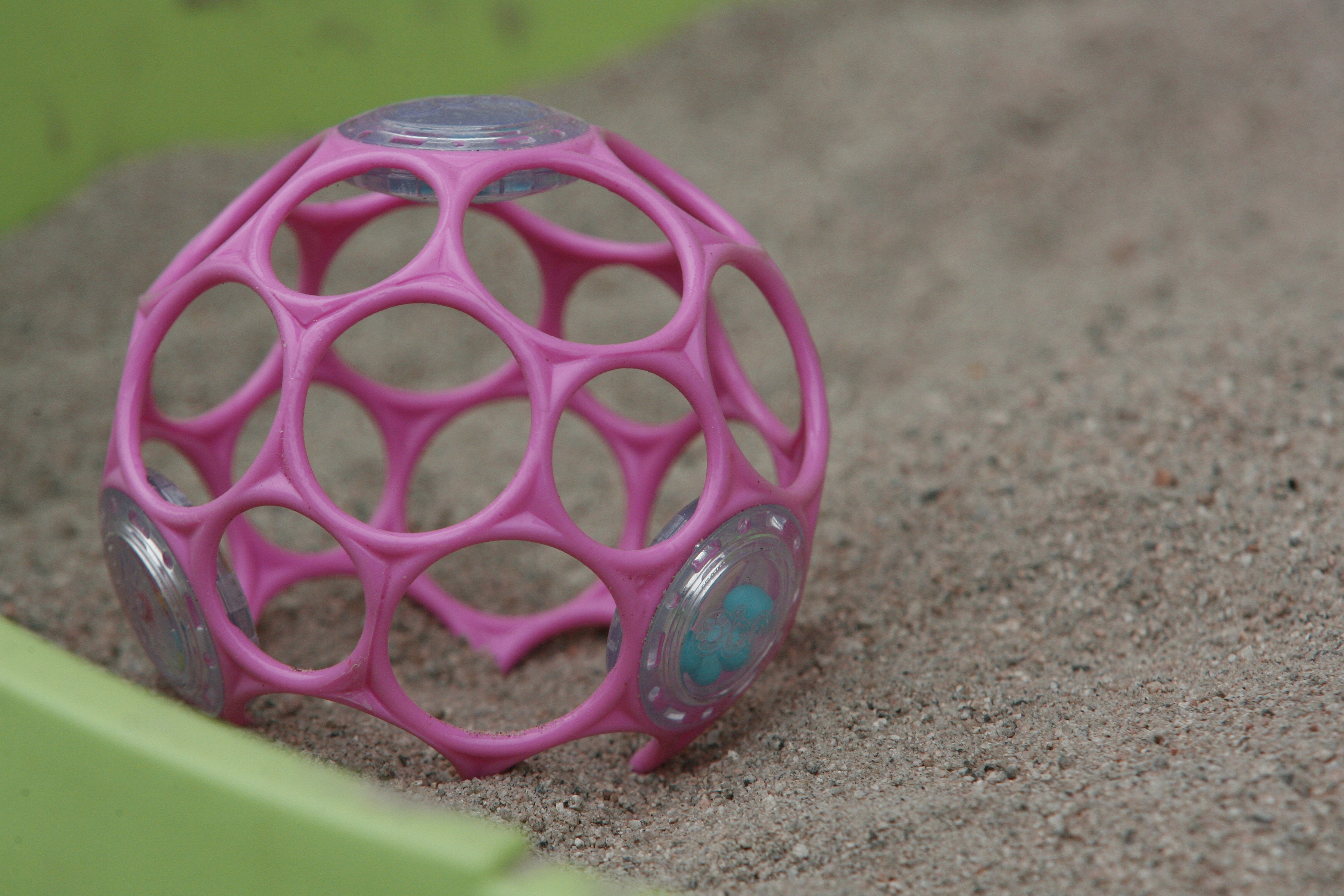 Pink oball rests on a bed of sand.