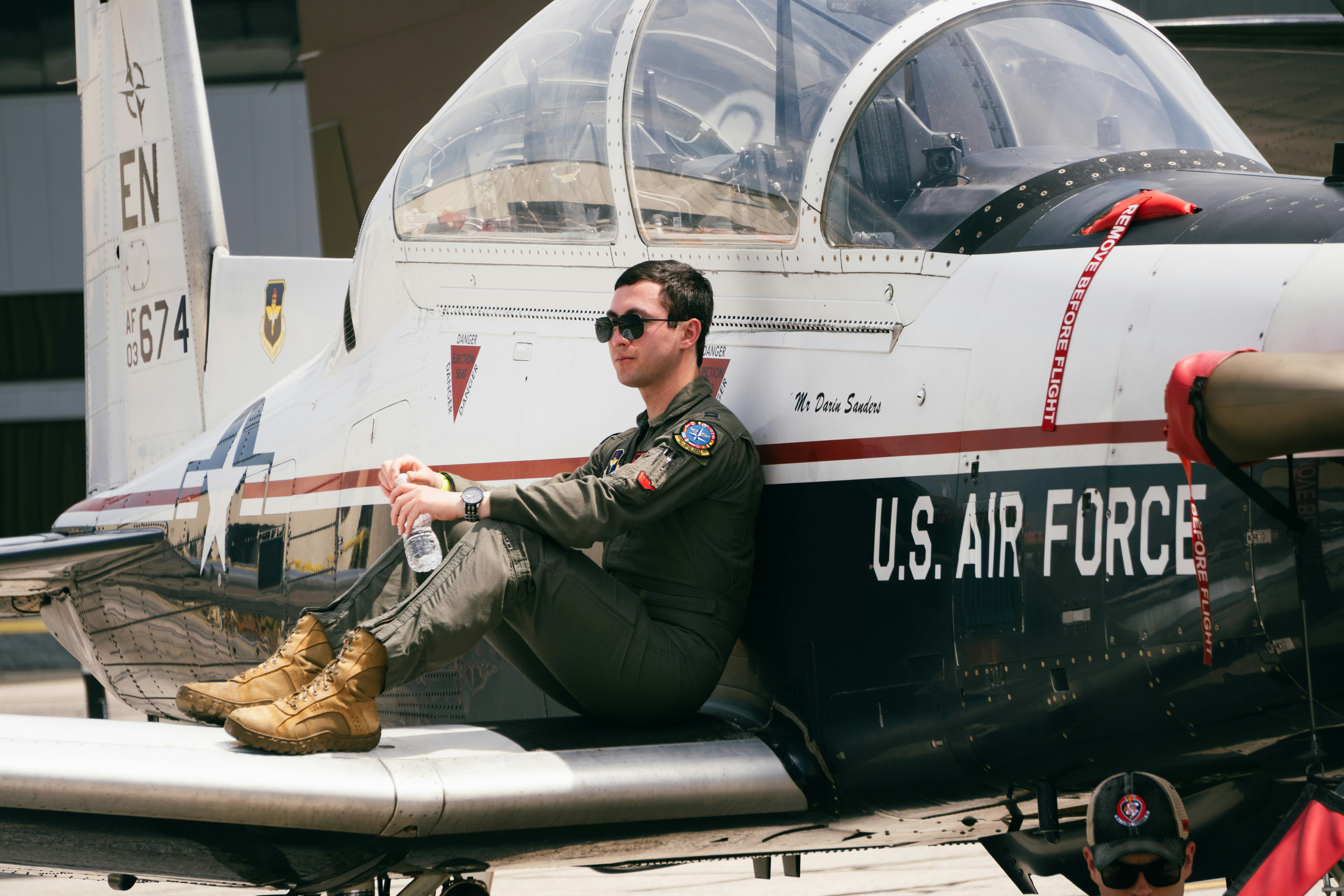 An air force pilot rests on the wing of a plane.