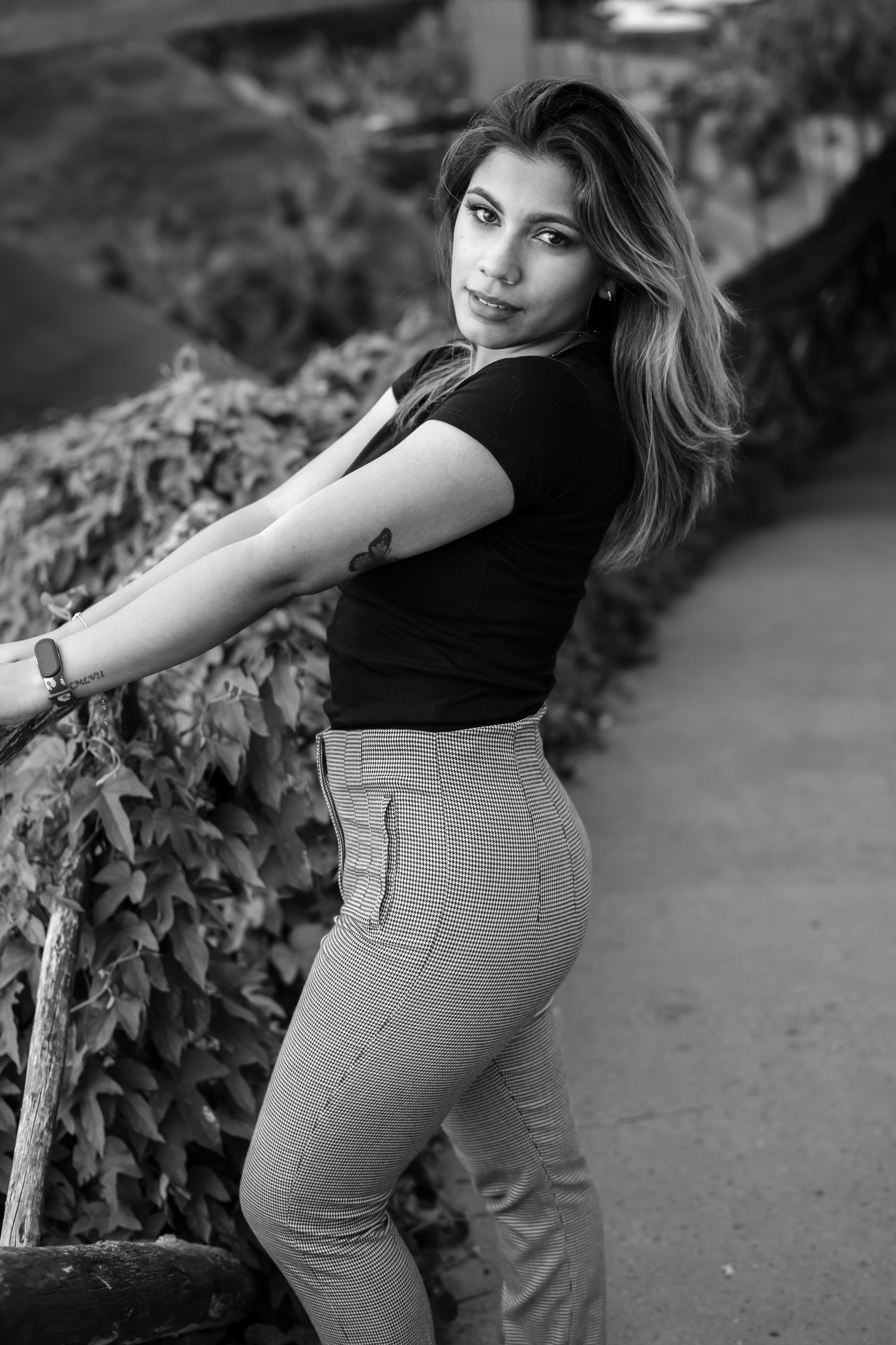 A young woman poses beside foliage.