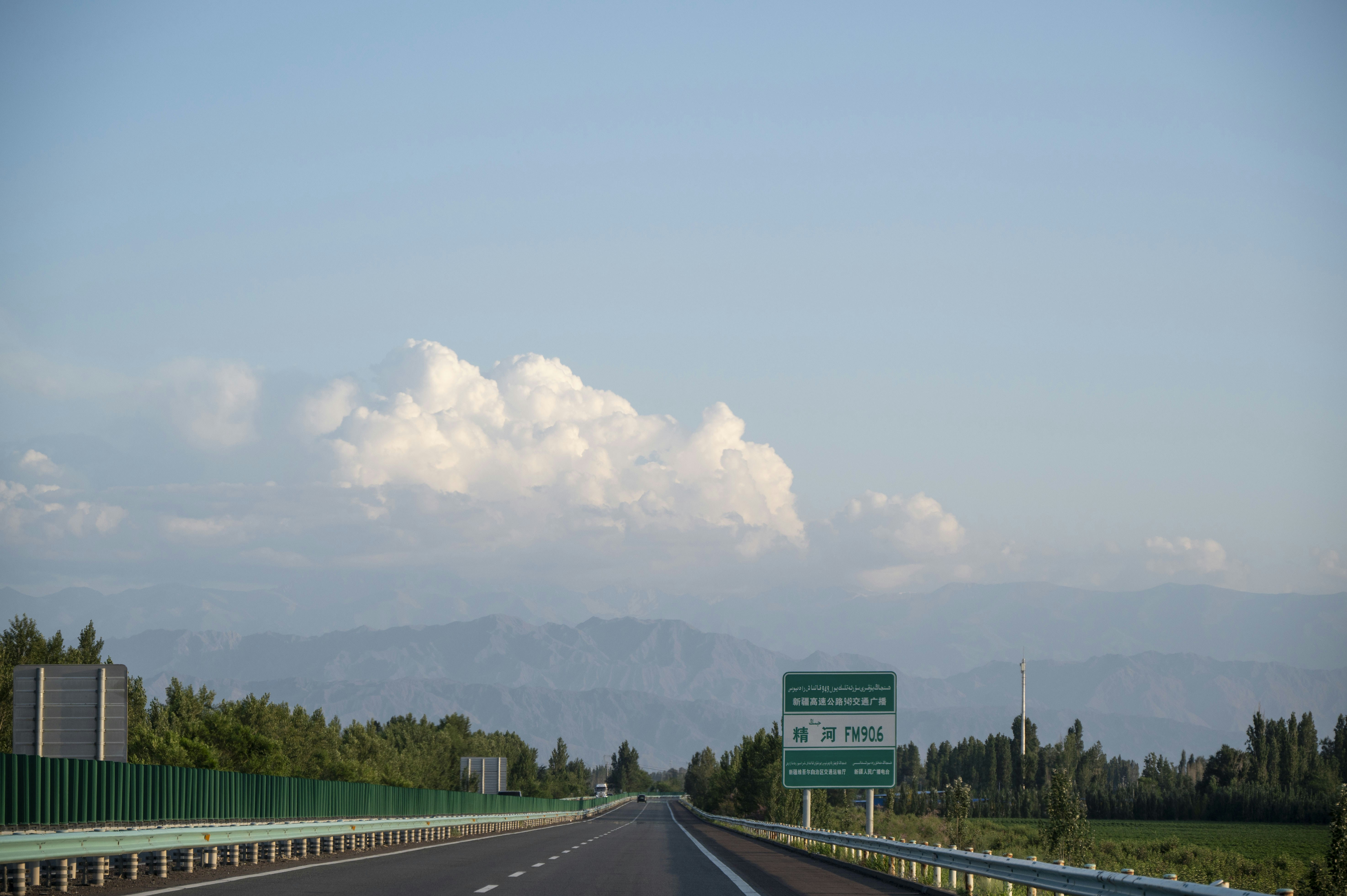 Empty highway with mountains and puffy clouds above.