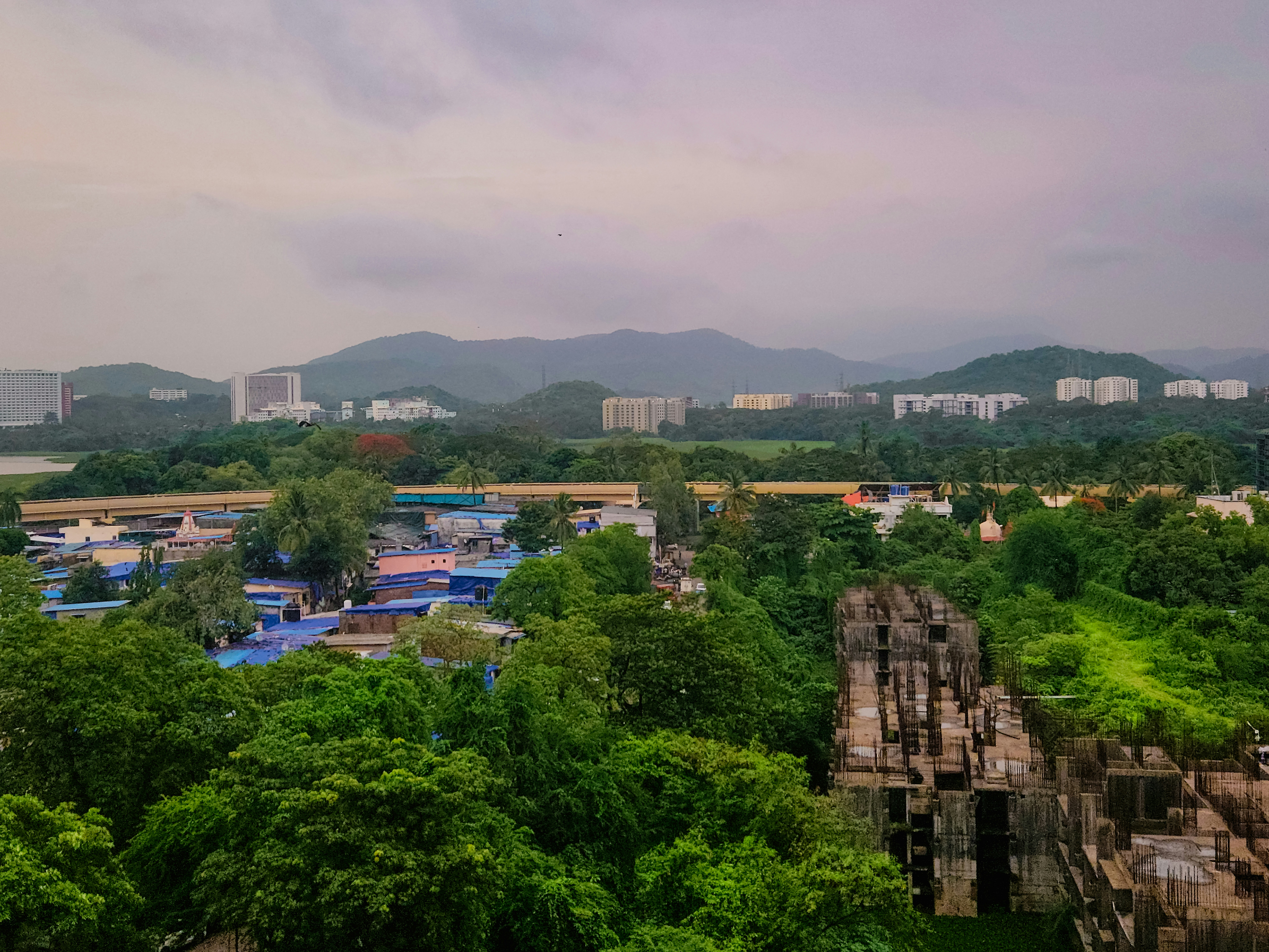 An abandoned construction site can be seen in Powai with IIT Powai Mumbai and the hills of Sanjay Gandhi National Park in the distance. | Scenic view of a city and mountains.
