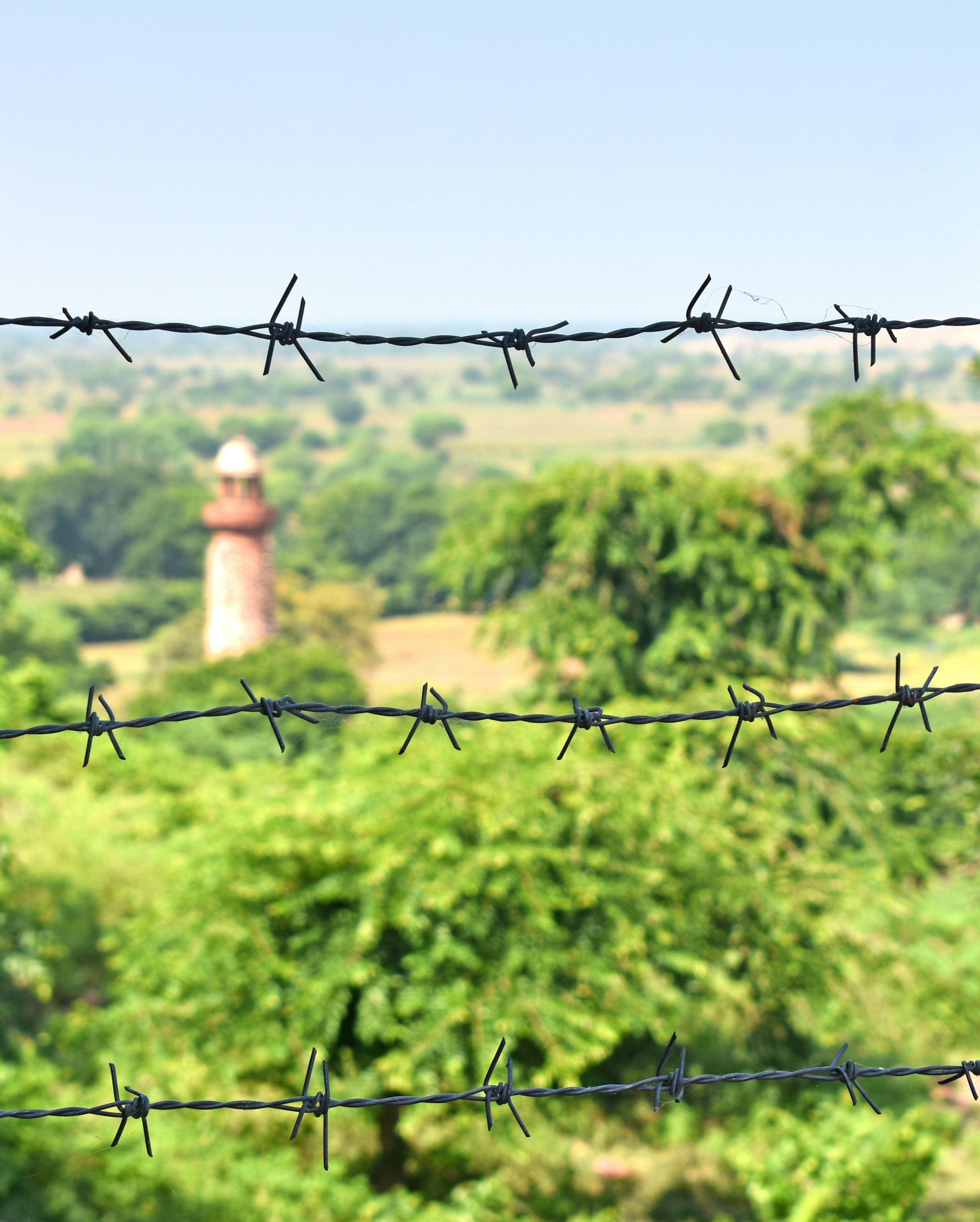 Barbed wire frames a distant structure and landscape. photo – Free ...