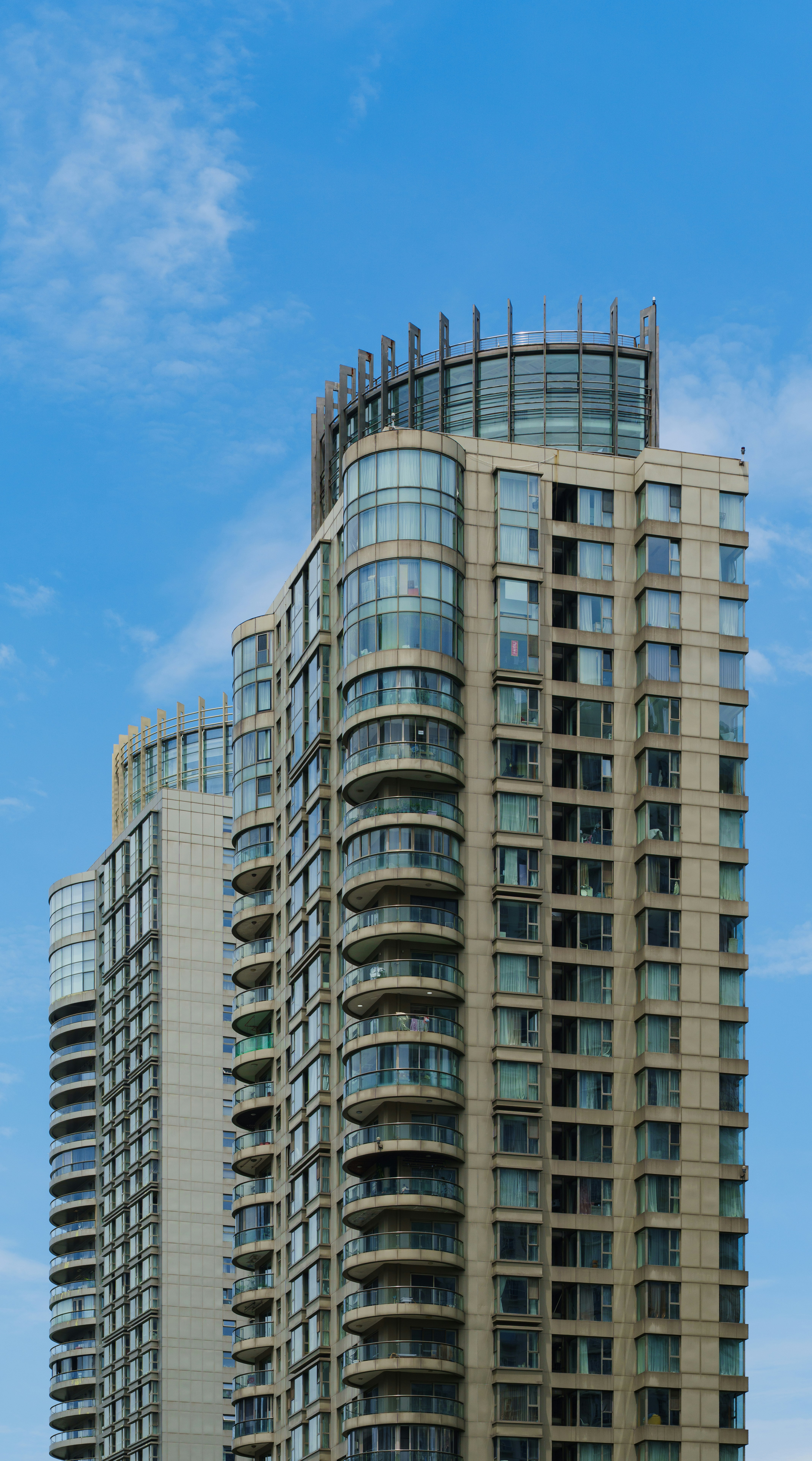Apartment building with curved balconies | Tall buildings against a bright, blue sky.