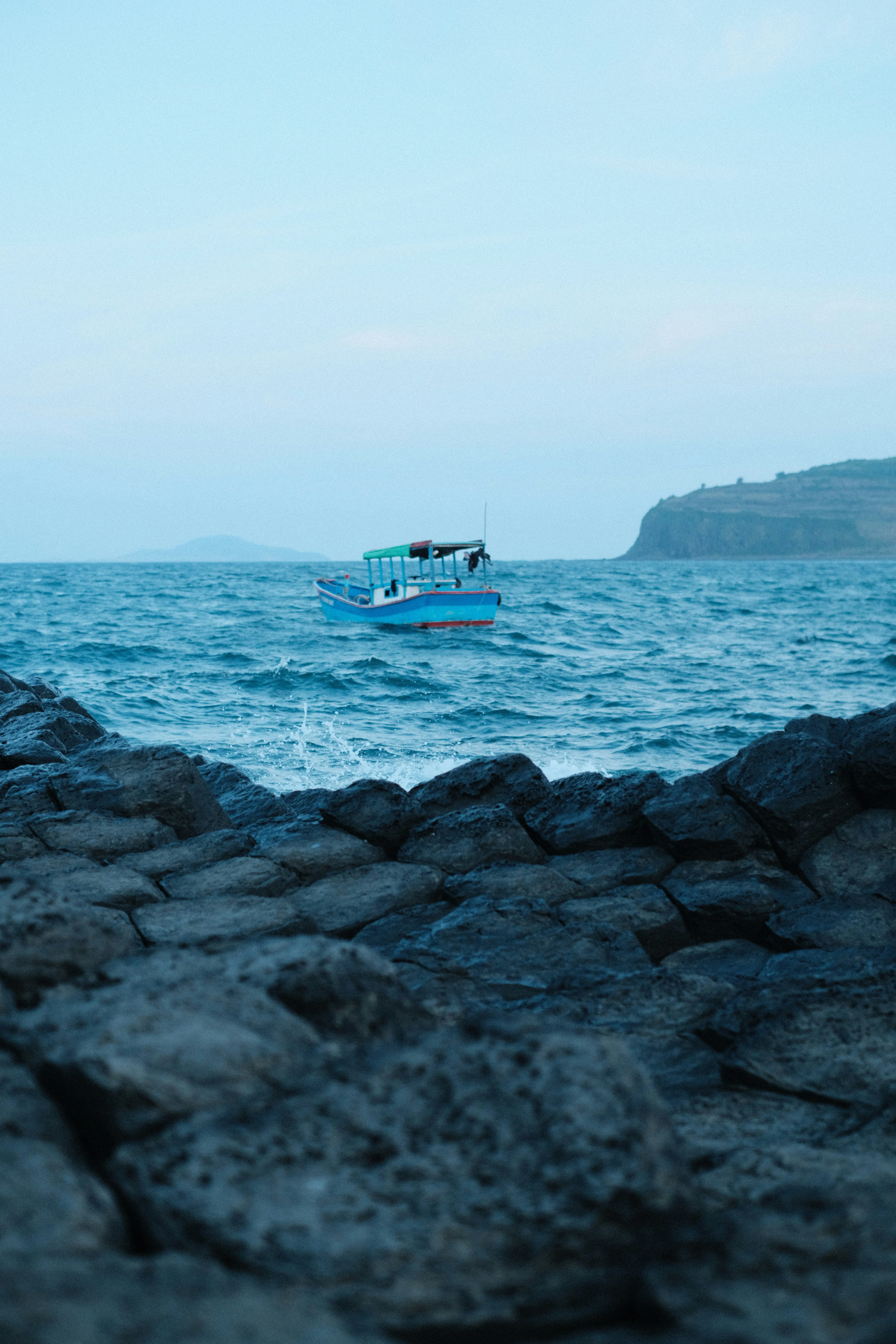A blue boat floats on the sea.