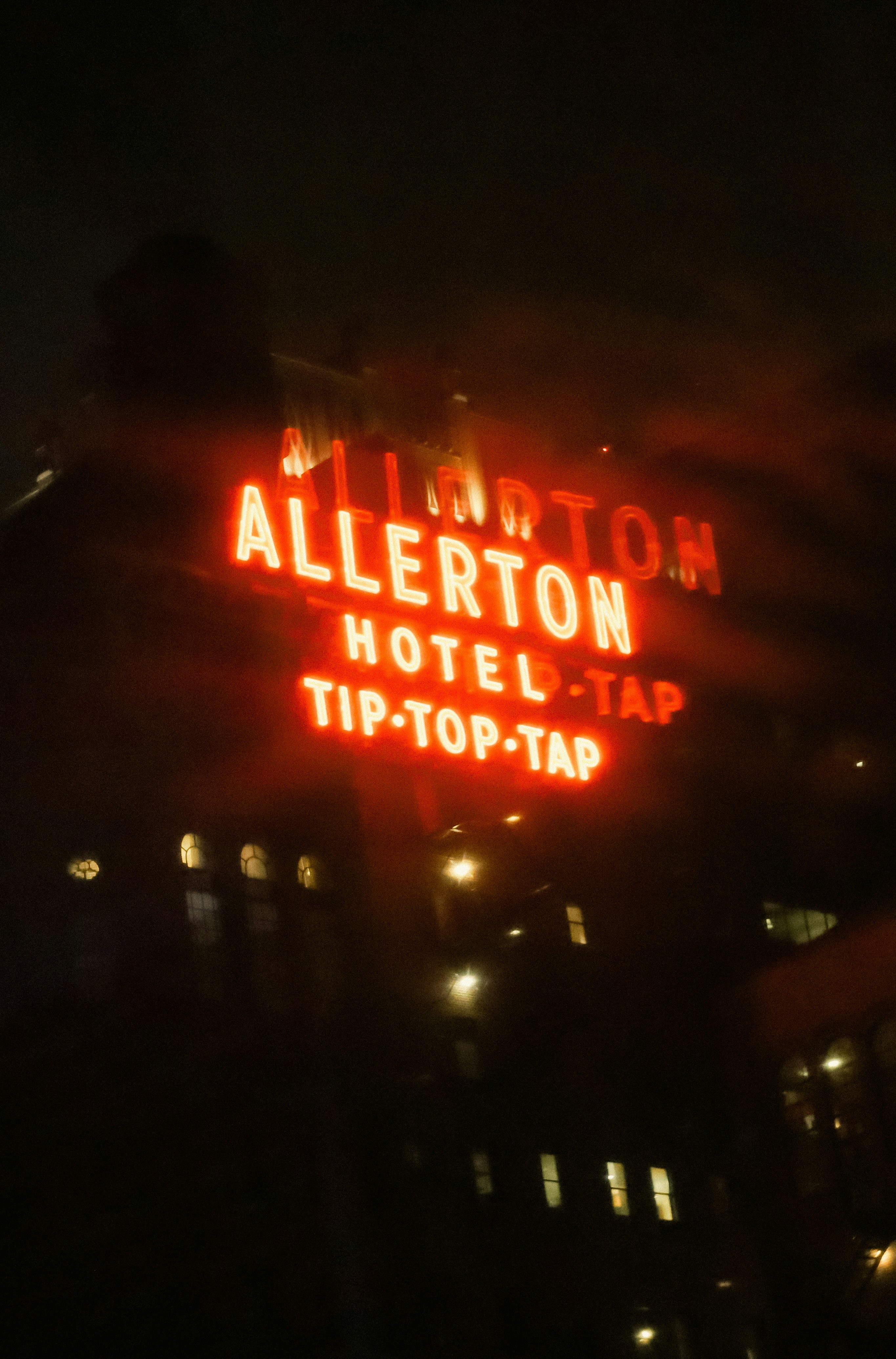 Illuminated vintage hotel sign glows brightly against the night sky, showcasing its iconic lettering and nostalgic charm.