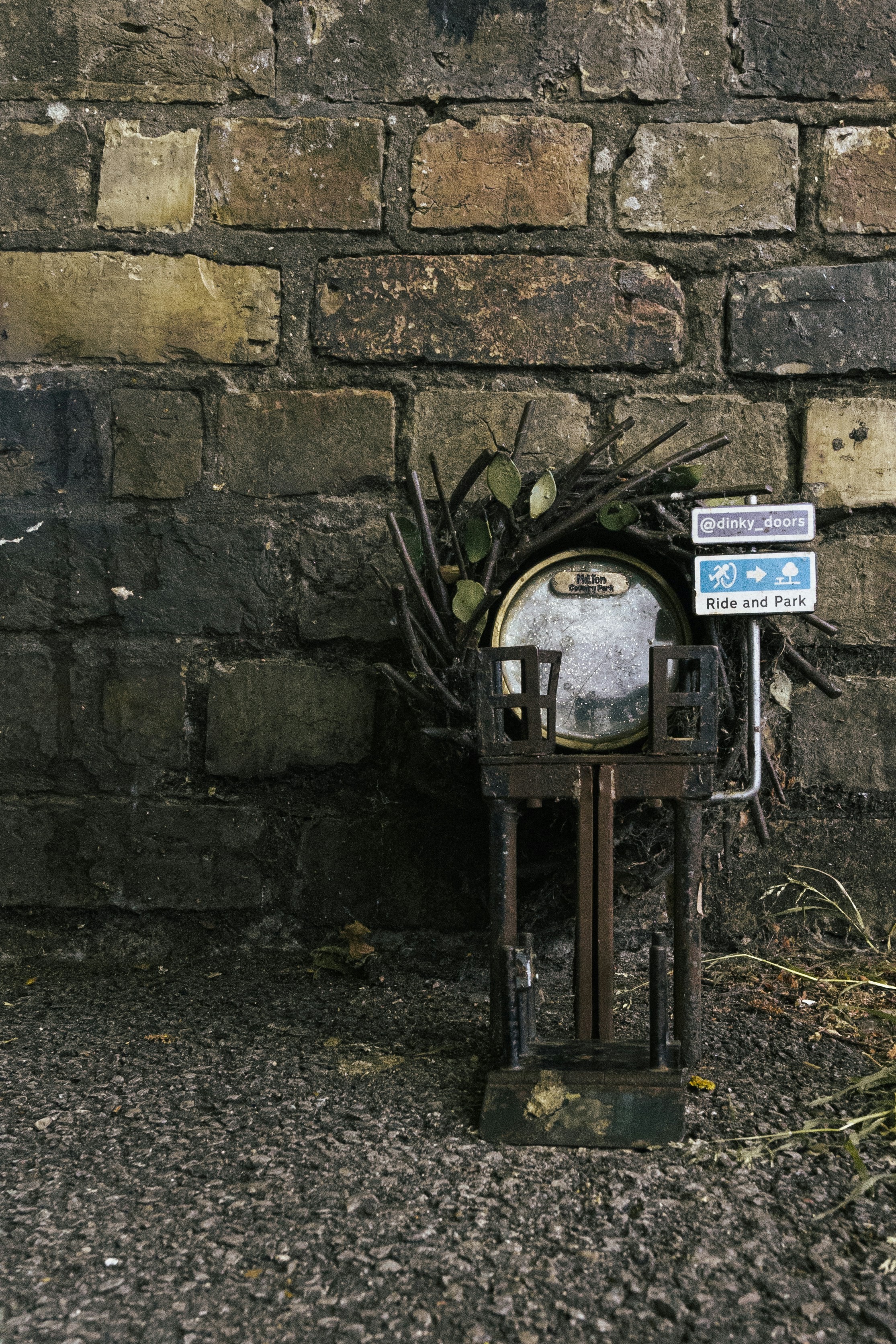 A miniature scene decorates a brick wall outdoors.