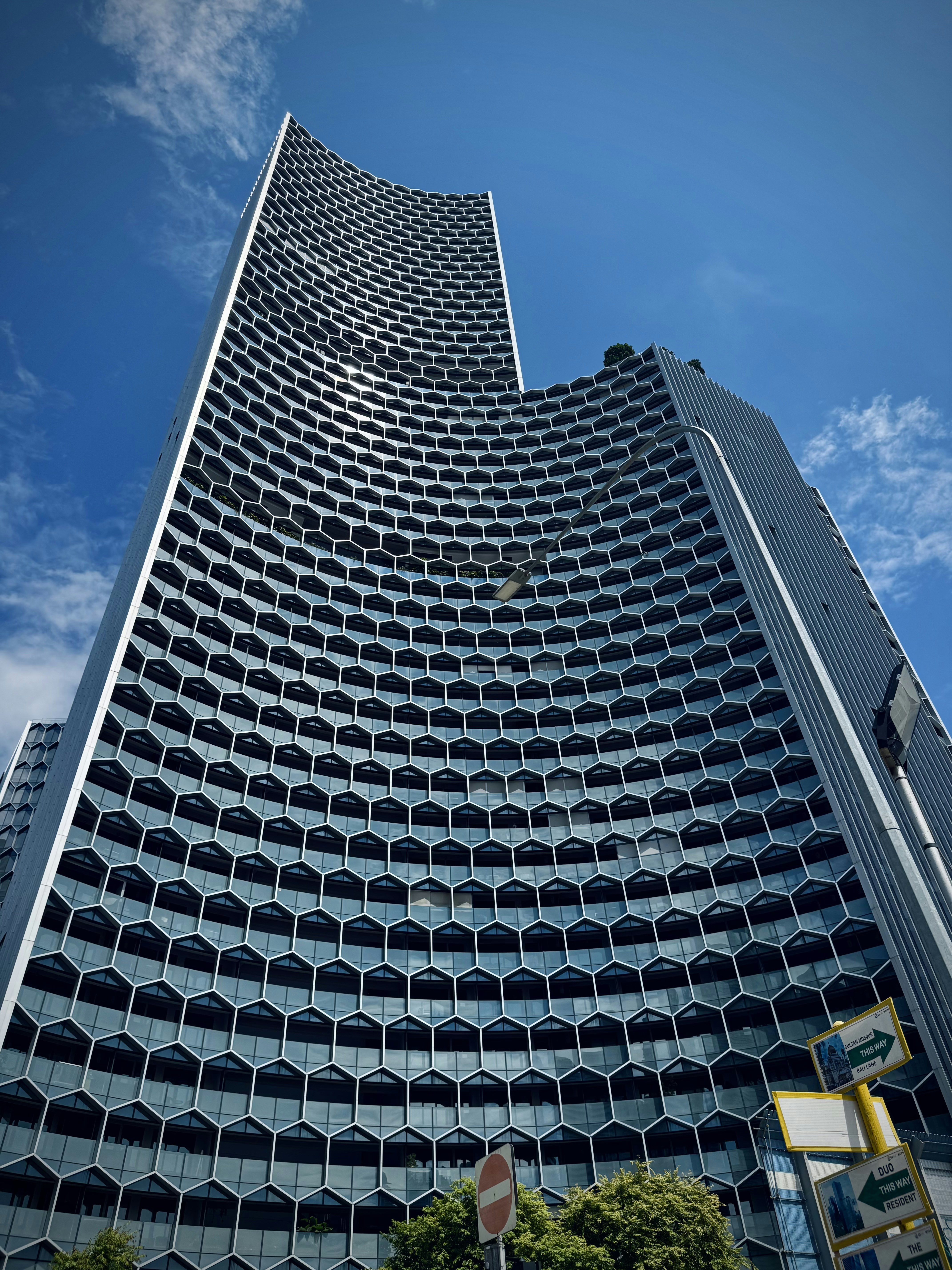 Hexagonal Curtain: A Leaning Glass Tower Reaching for the Sky