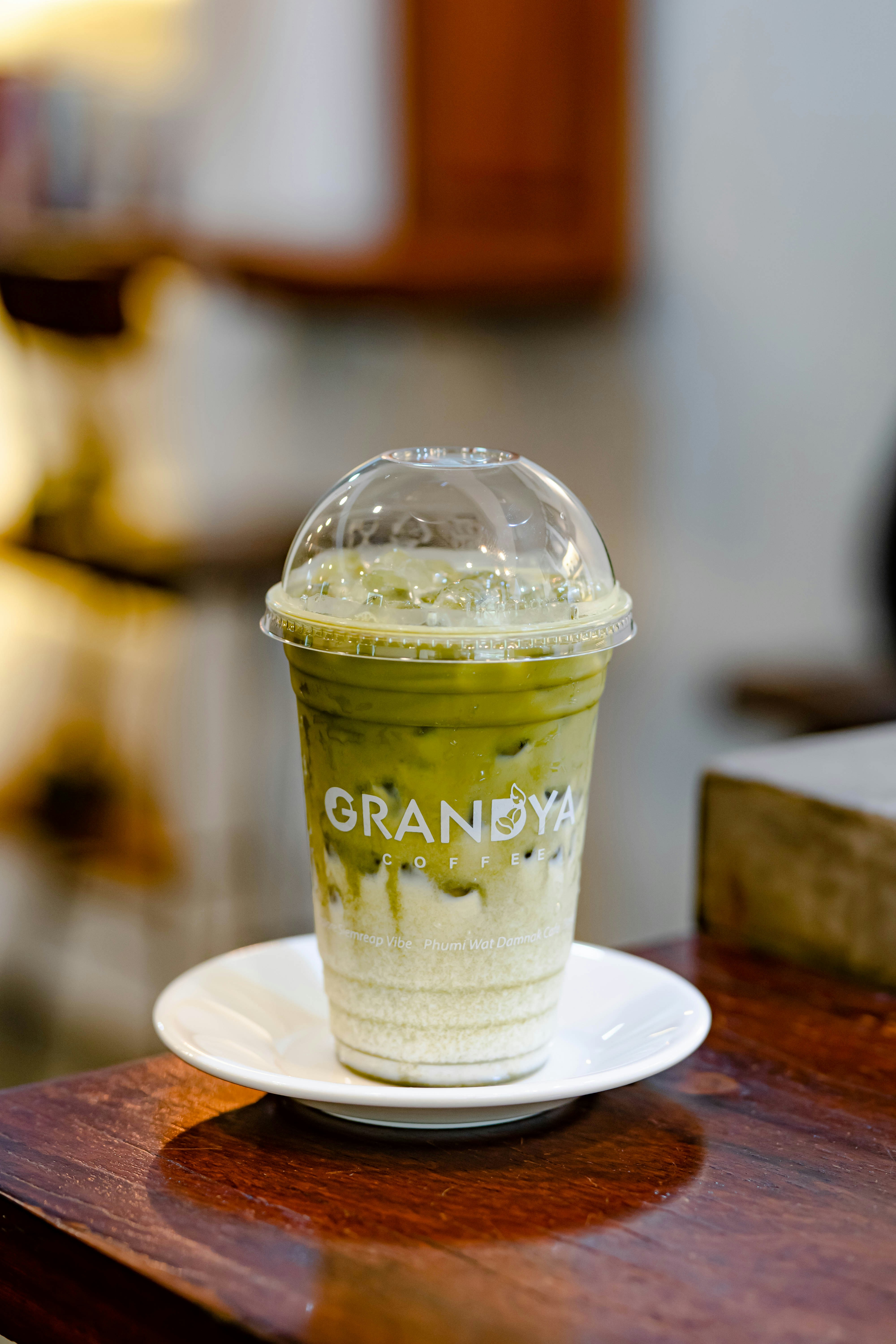 Green Matcha Latte in a Glass Dome, Center Stage on a Wooden Bar