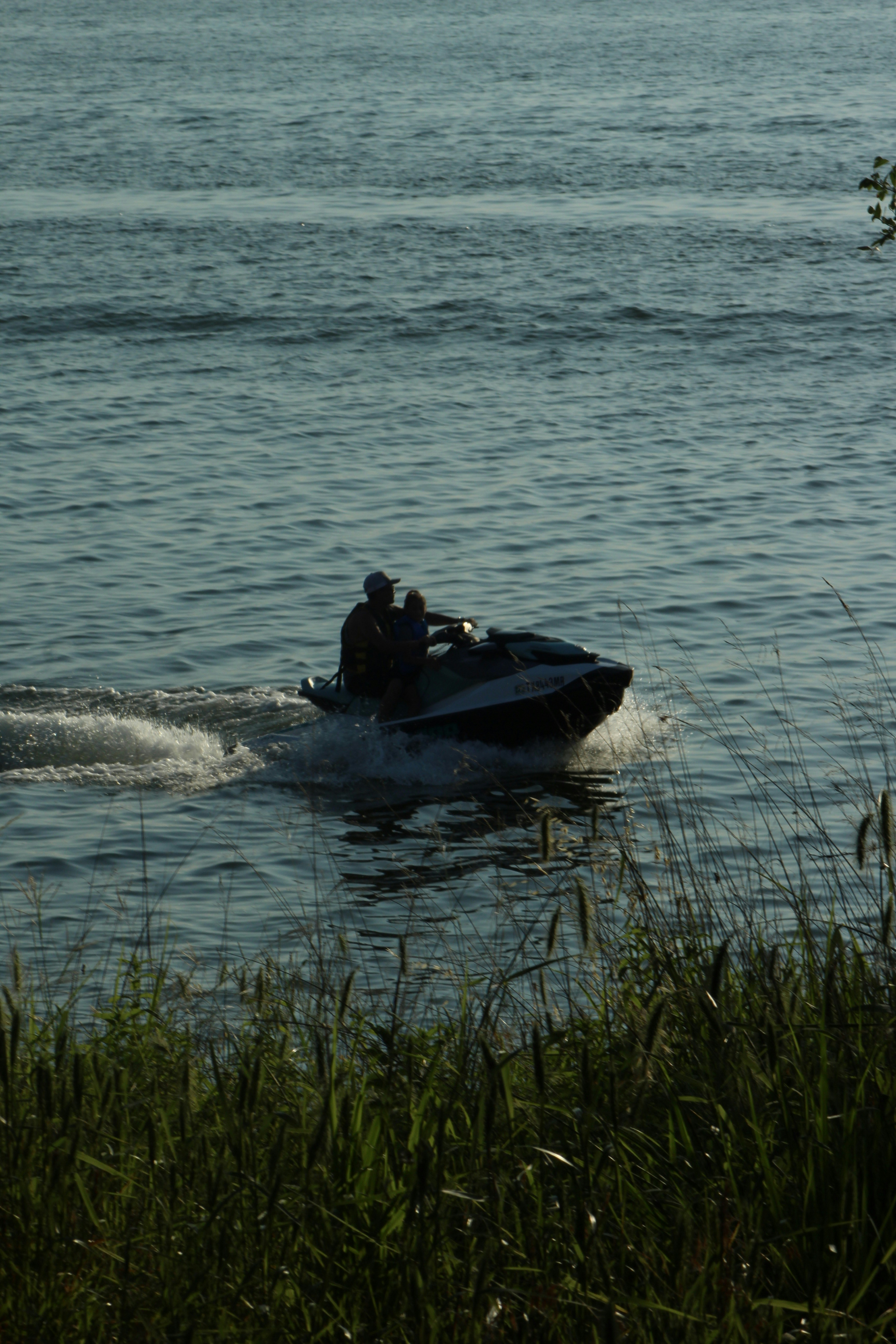 Twin Riders on a Jet Ski Skim a Glassy Lake at Dusk