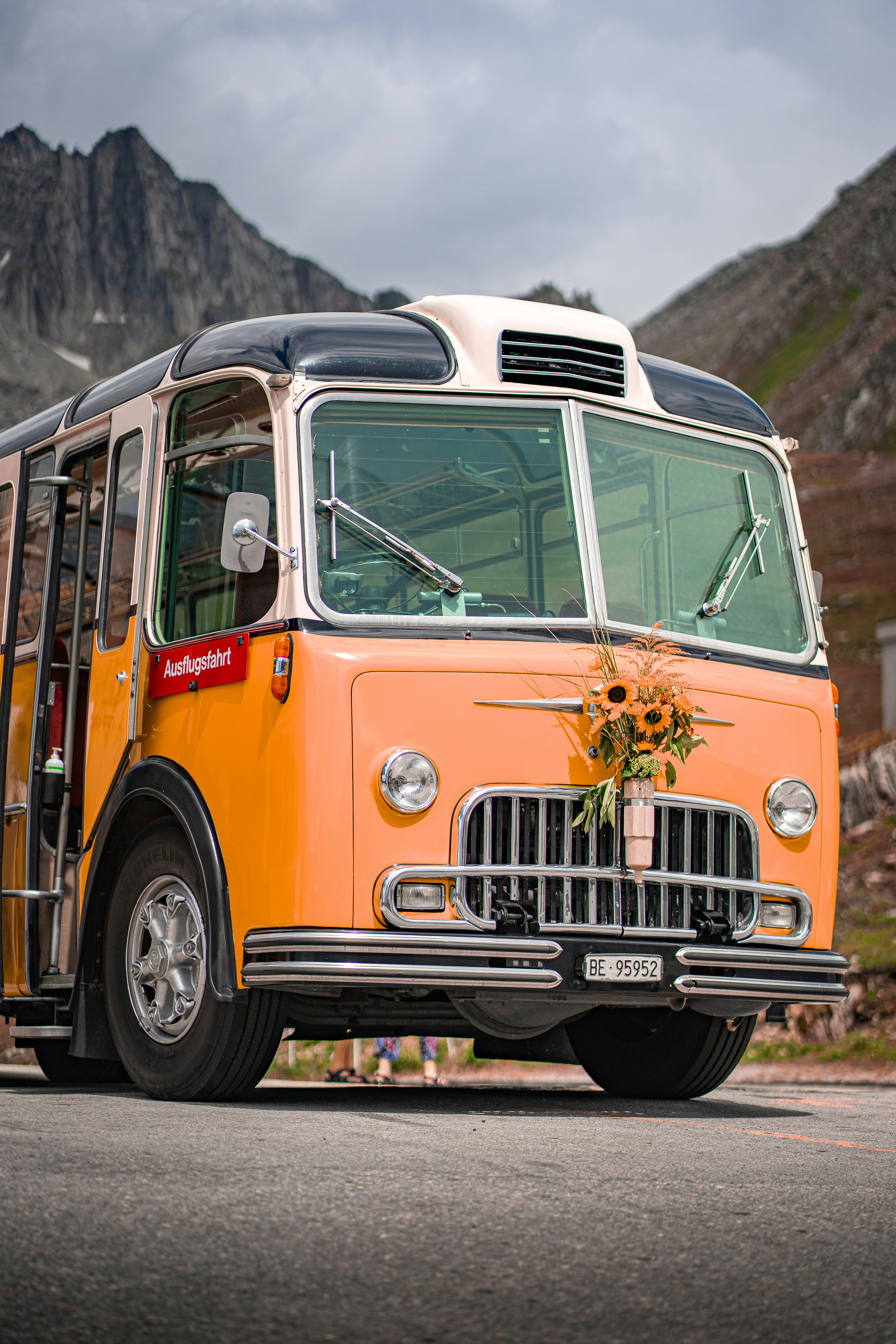 Sunflower Bouquet on a Retro Orange Bus Amid Alpine Backdrop