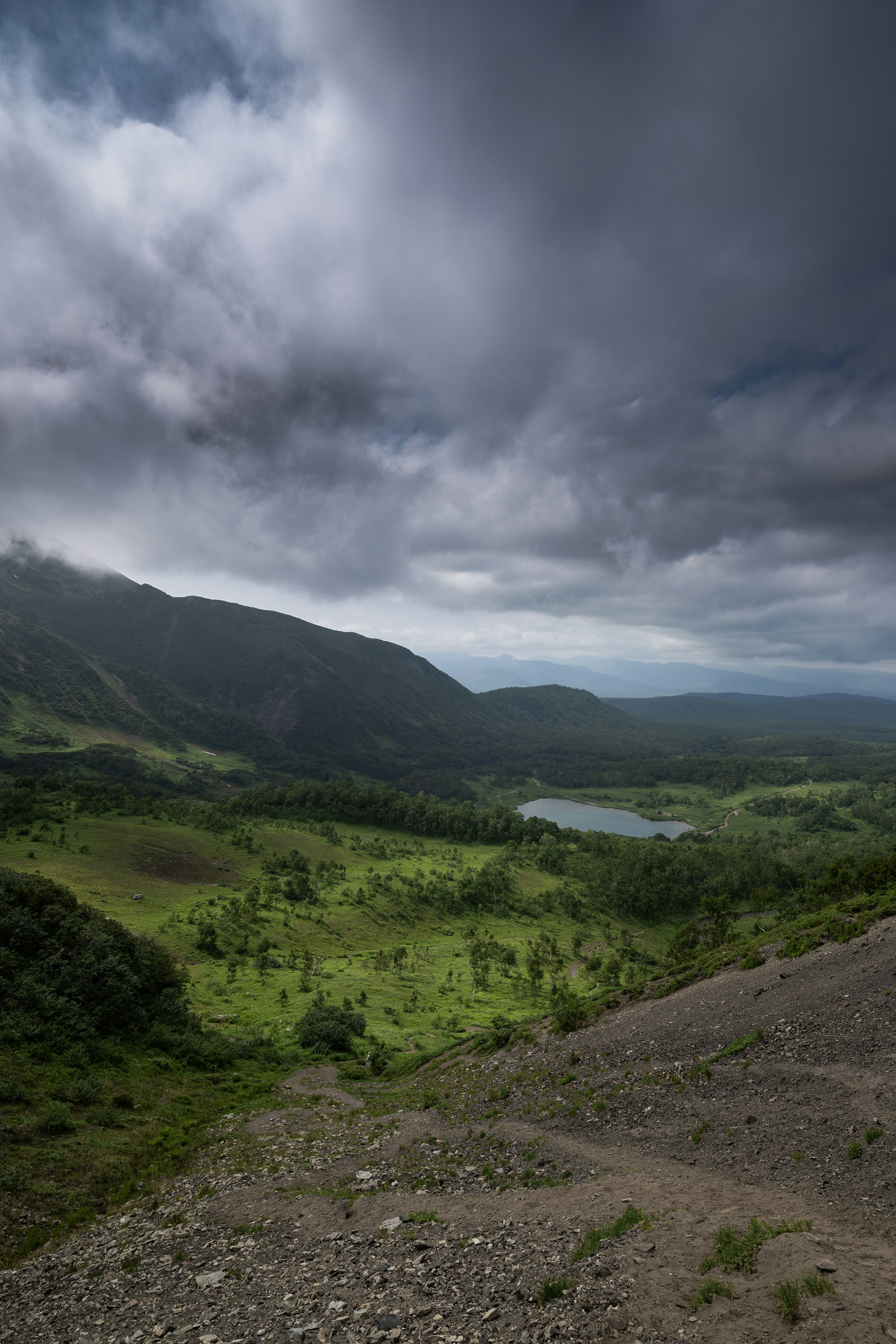 Vachkazhets mountain range (Kamchatka - 53,081395, 157,929445) | Green valley and mountains under a cloudy sky.