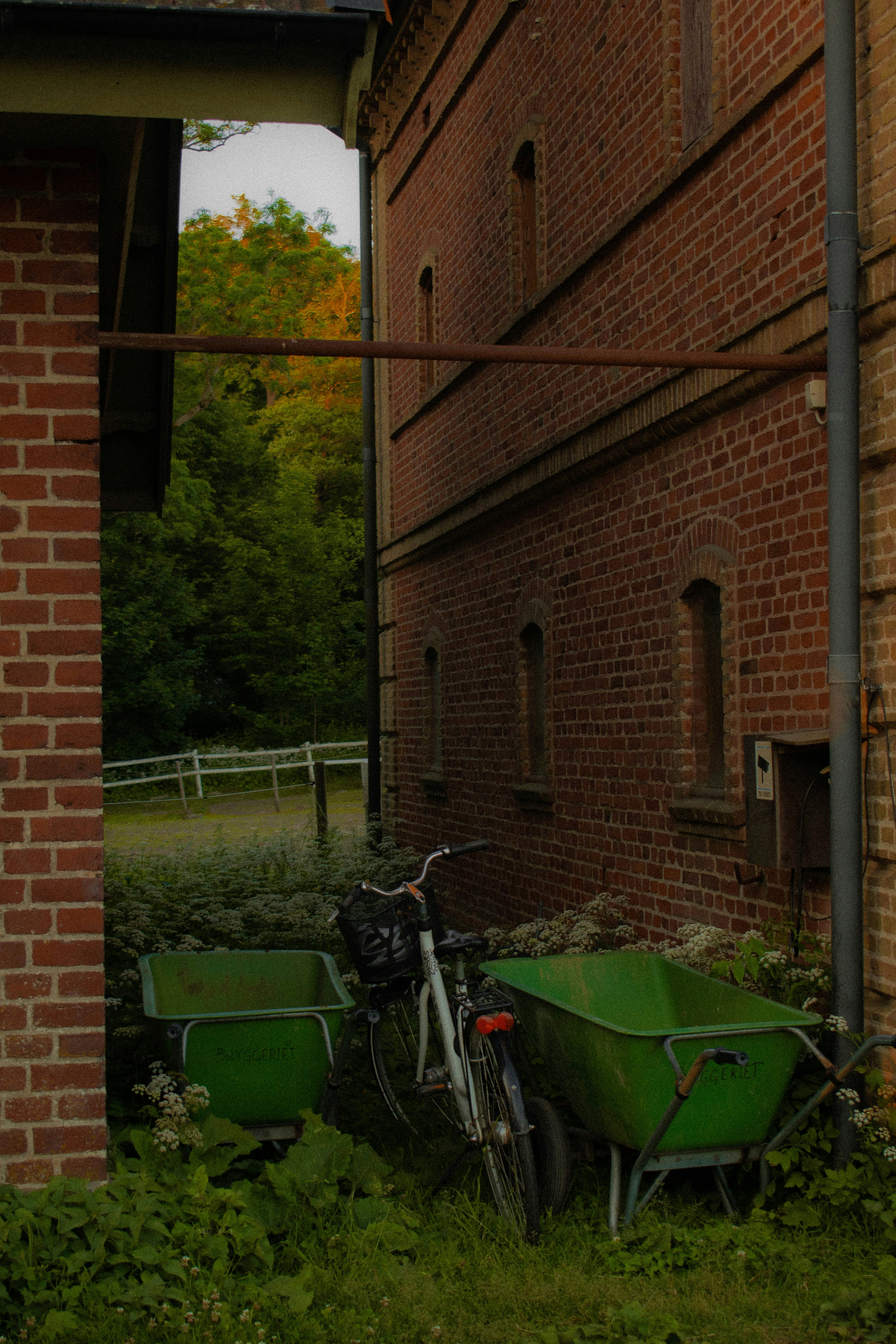 A bicycle rests next to two green wheelbarrows.