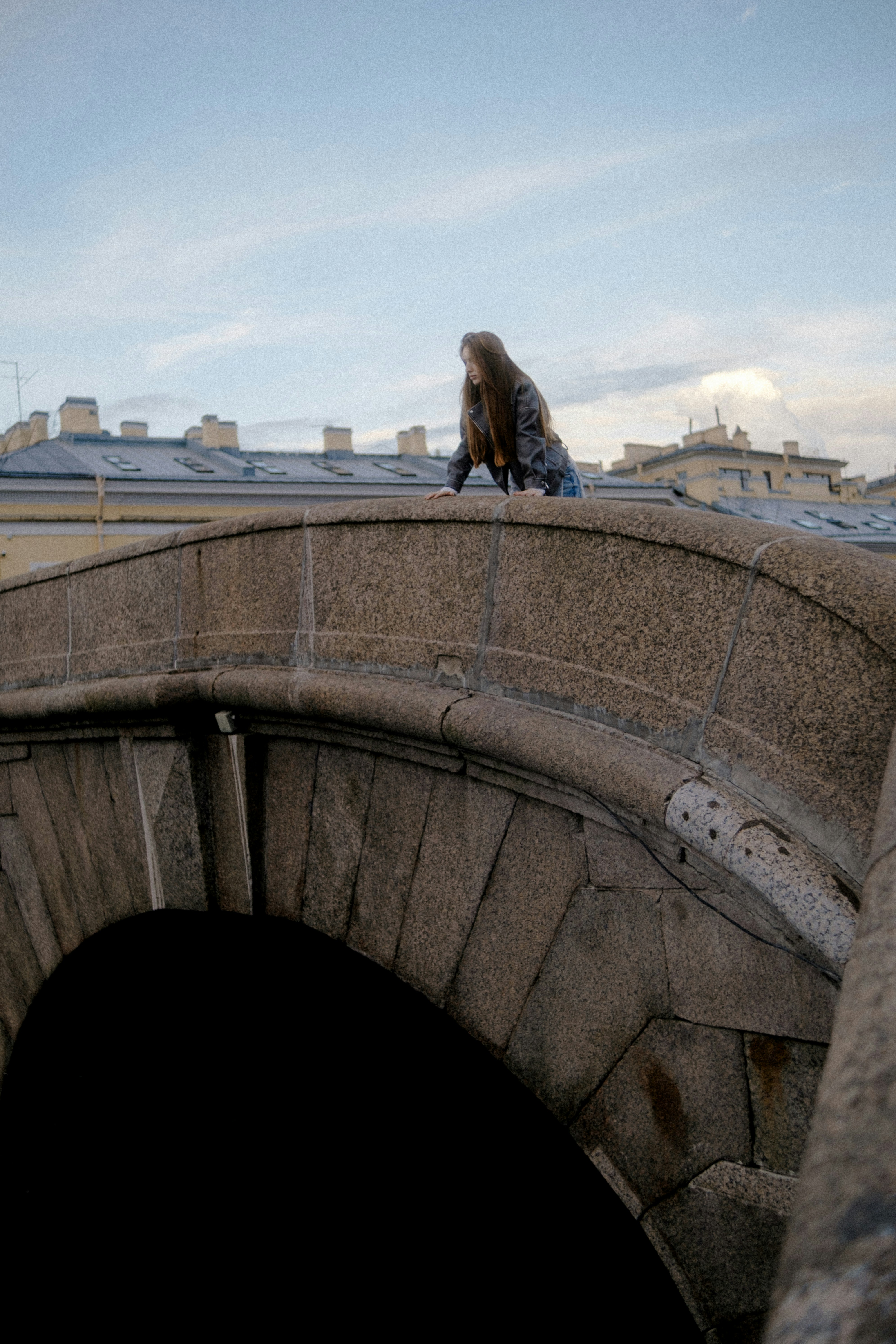 Over the Arch: A lone figure peers toward the city from a weathered bridge