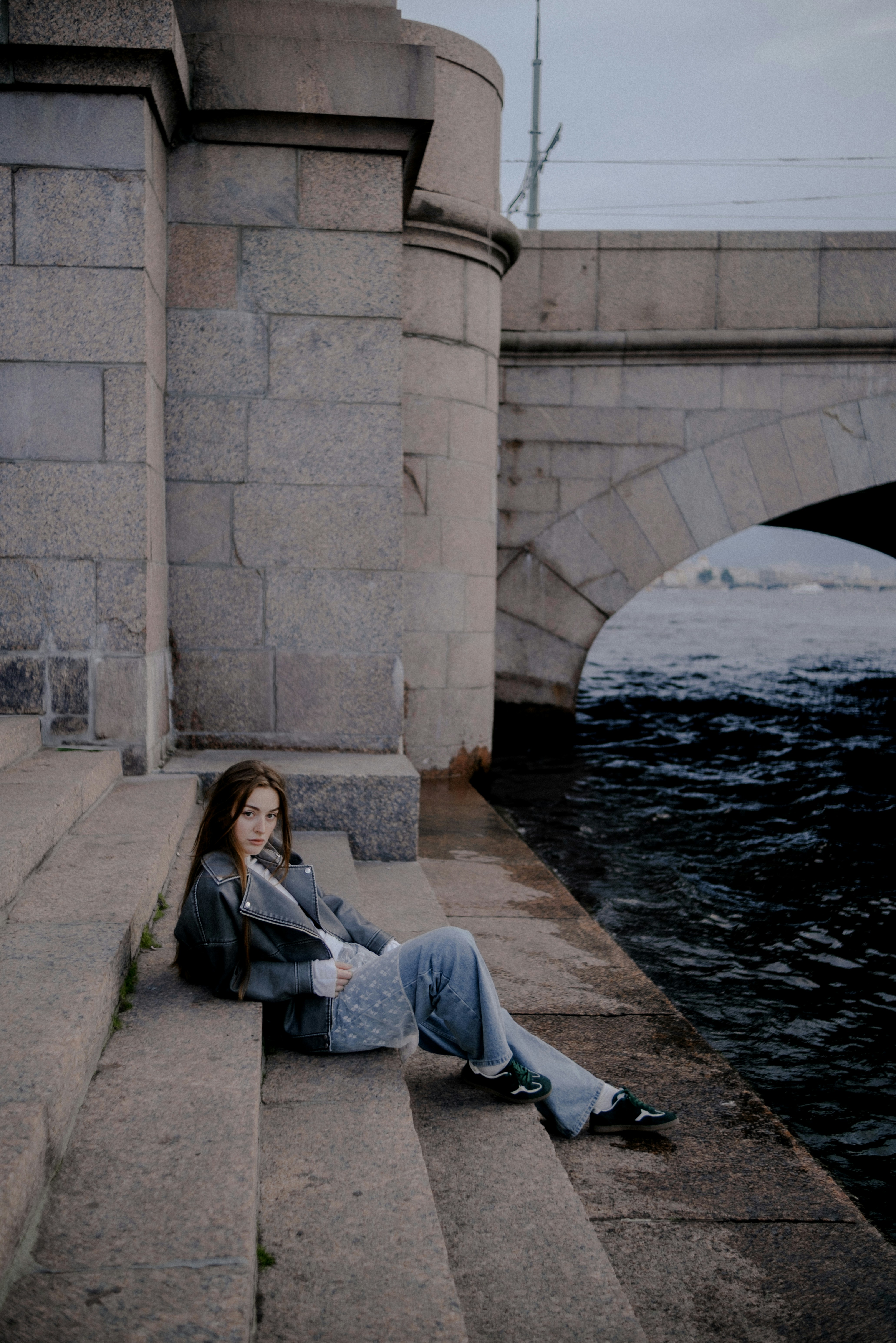 Edge of the River: a quiet portrait on stone steps beneath the arch