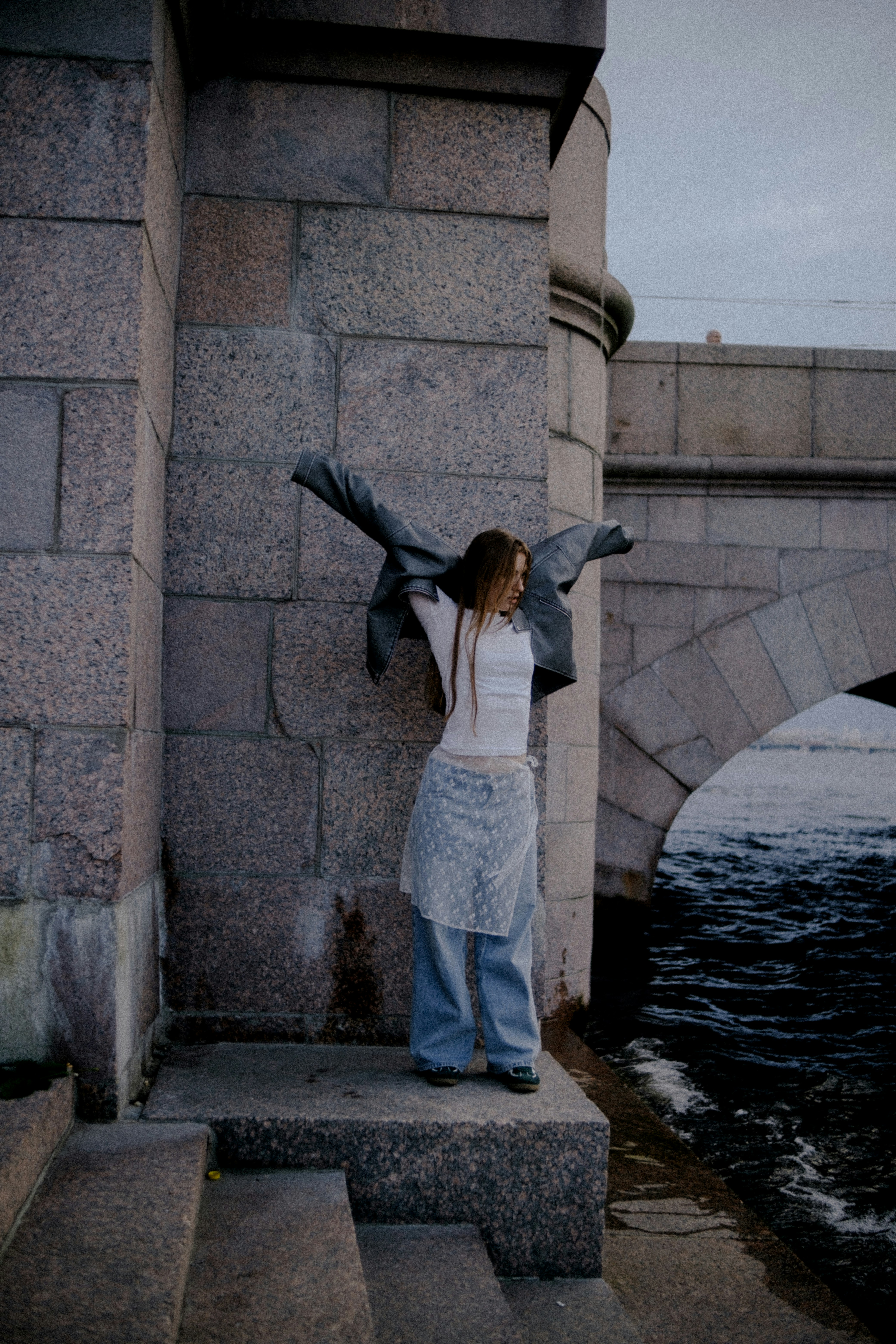 Denim Wings by the River: A Quiet Pose on the Stone Bridge