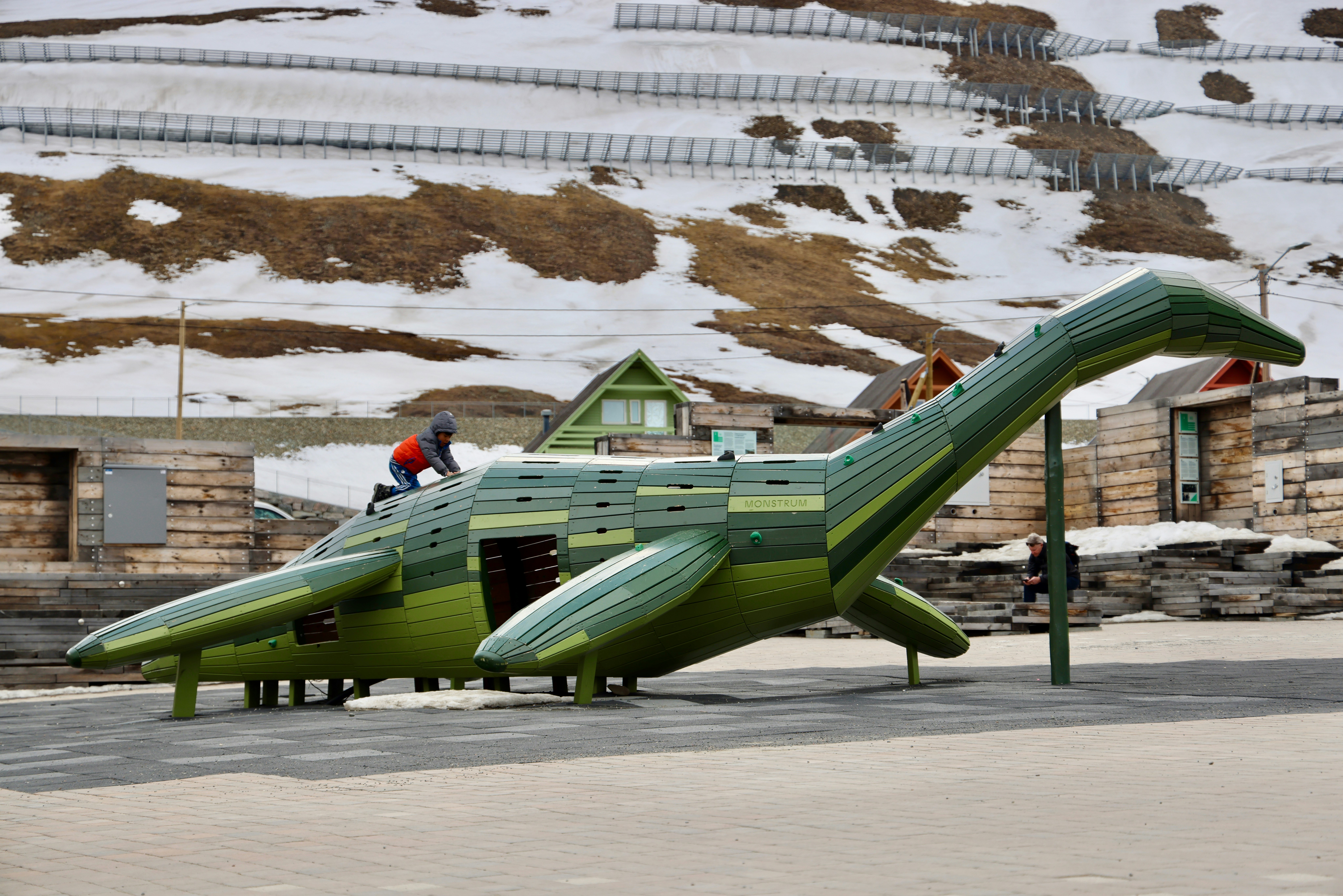 A green plane-shaped play structure with snowy hills.