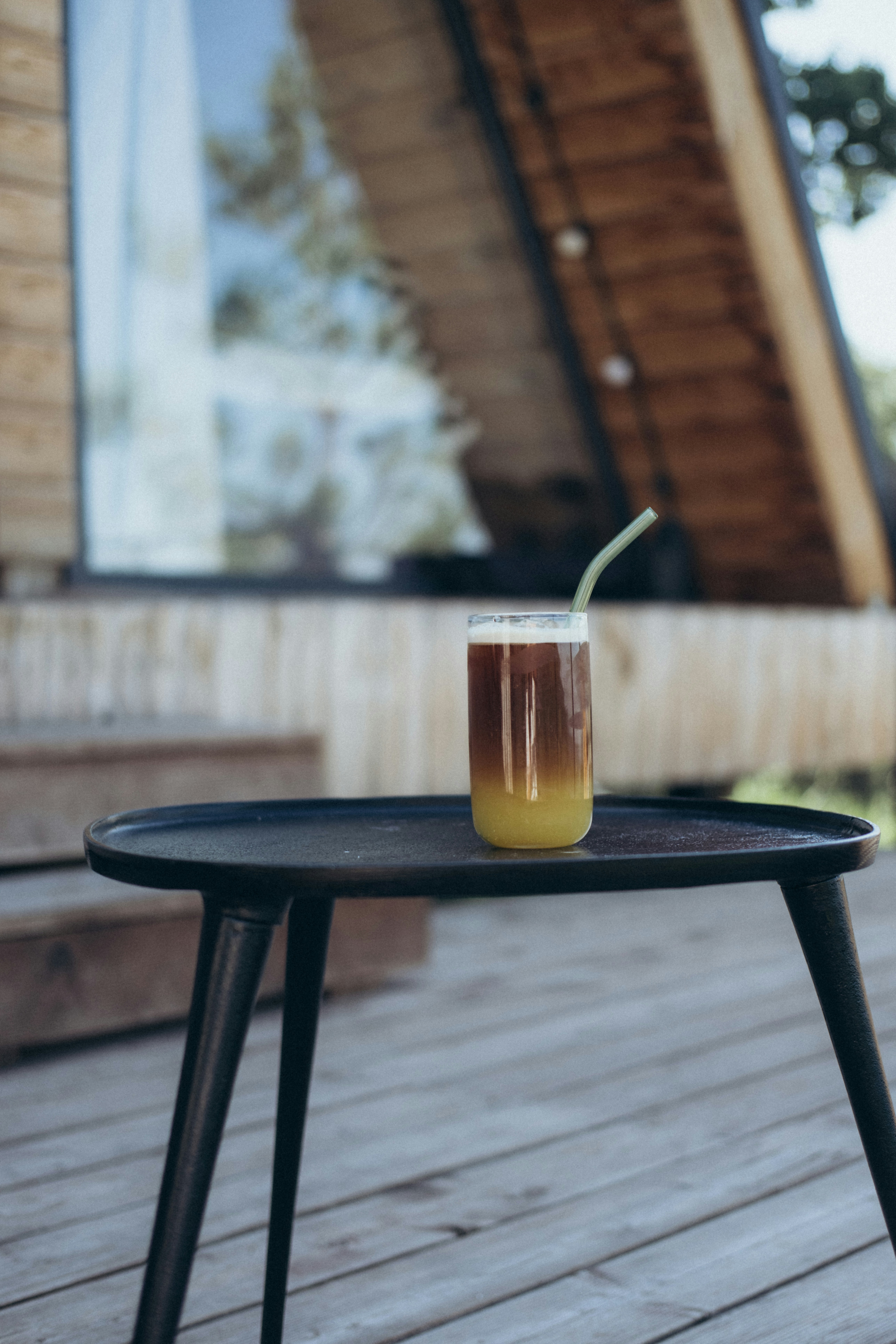 A refreshing drink sits on a black table, framed by a rustic wooden backdrop and natural light filtering through large windows.