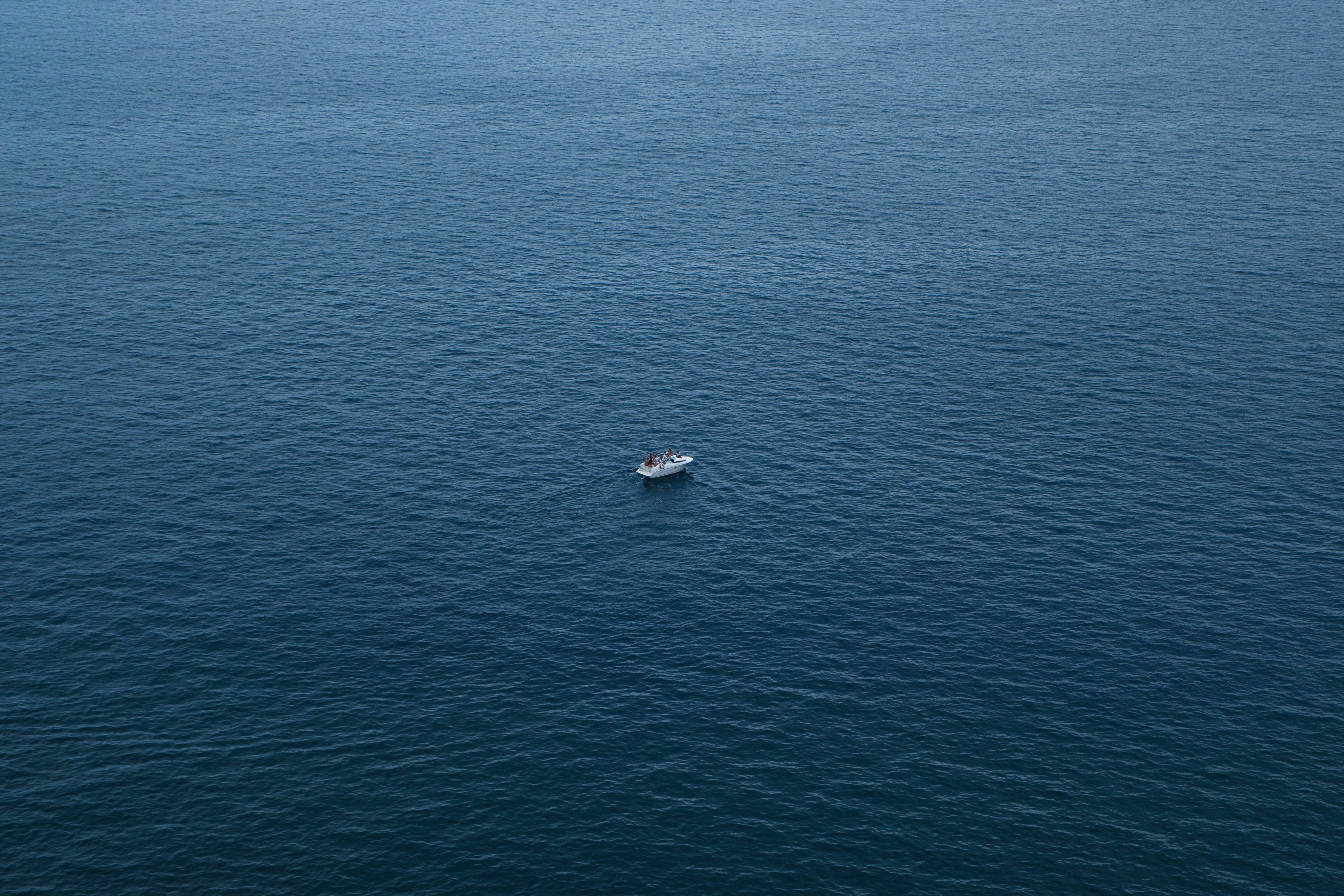 A boat floats alone on the blue ocean.