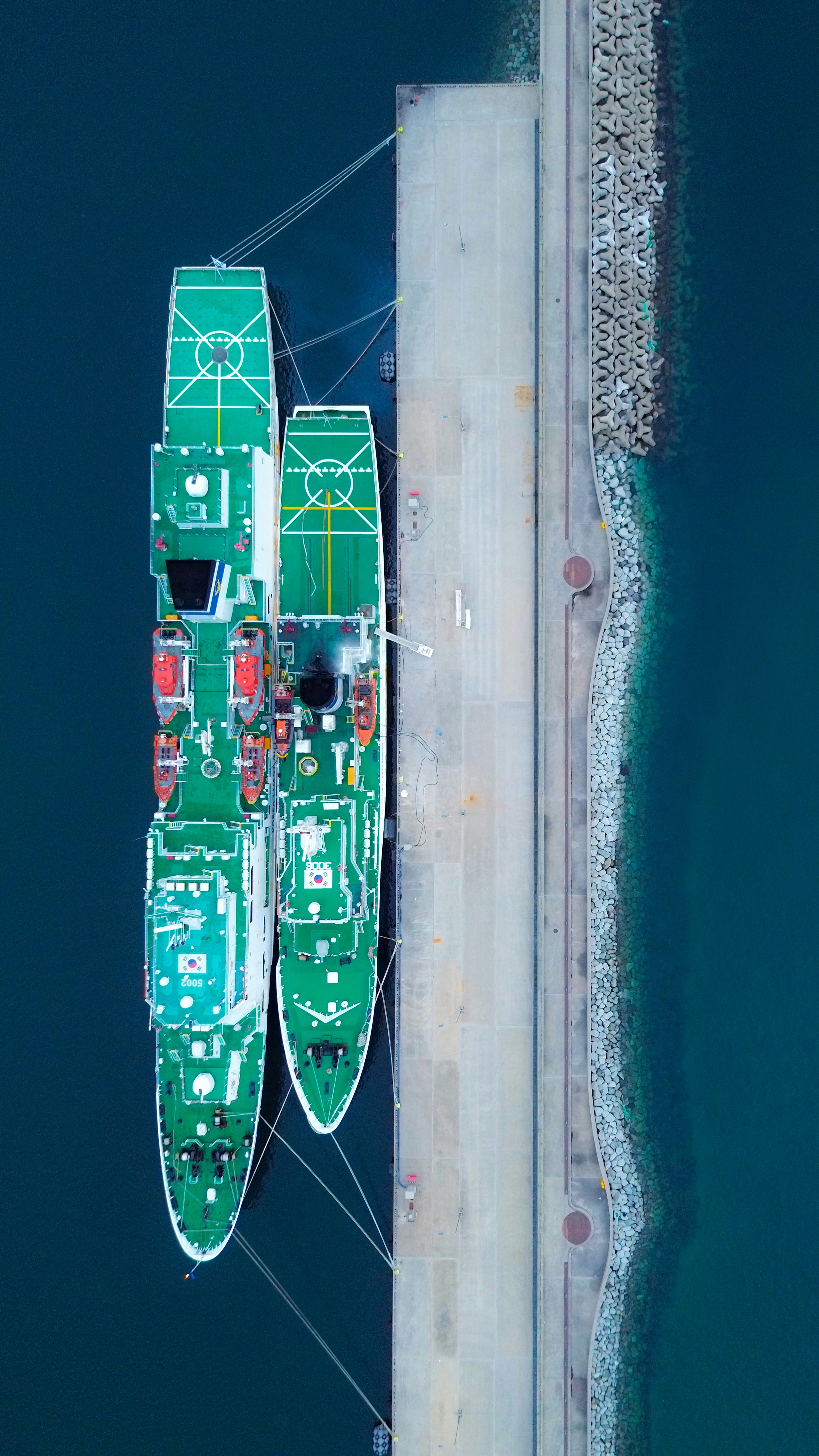 Emerald Hulls Moored Along a Narrow Jetty