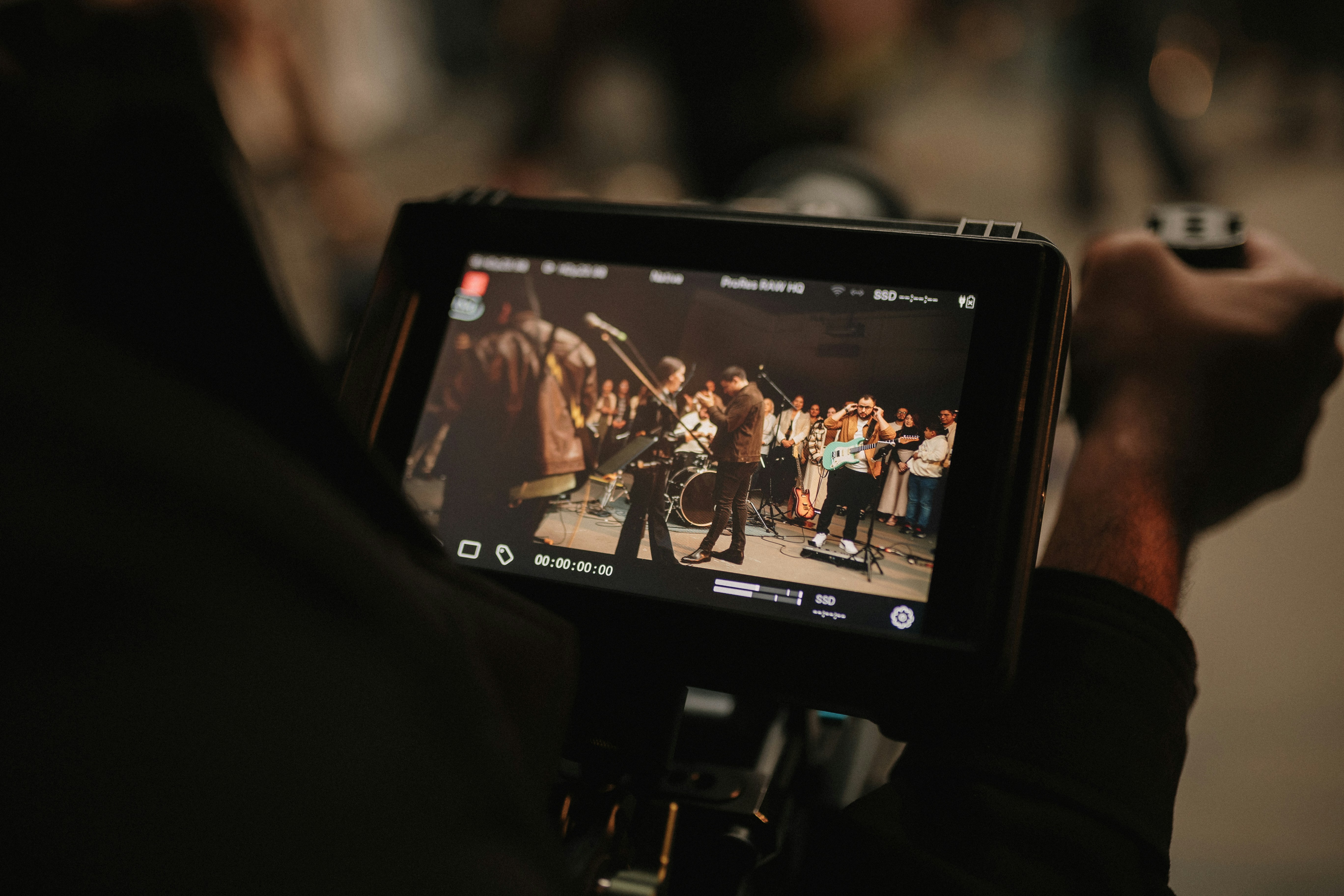 Filmmaker monitoring a live music performance on a monitor, showcasing the connection between artist and audience.