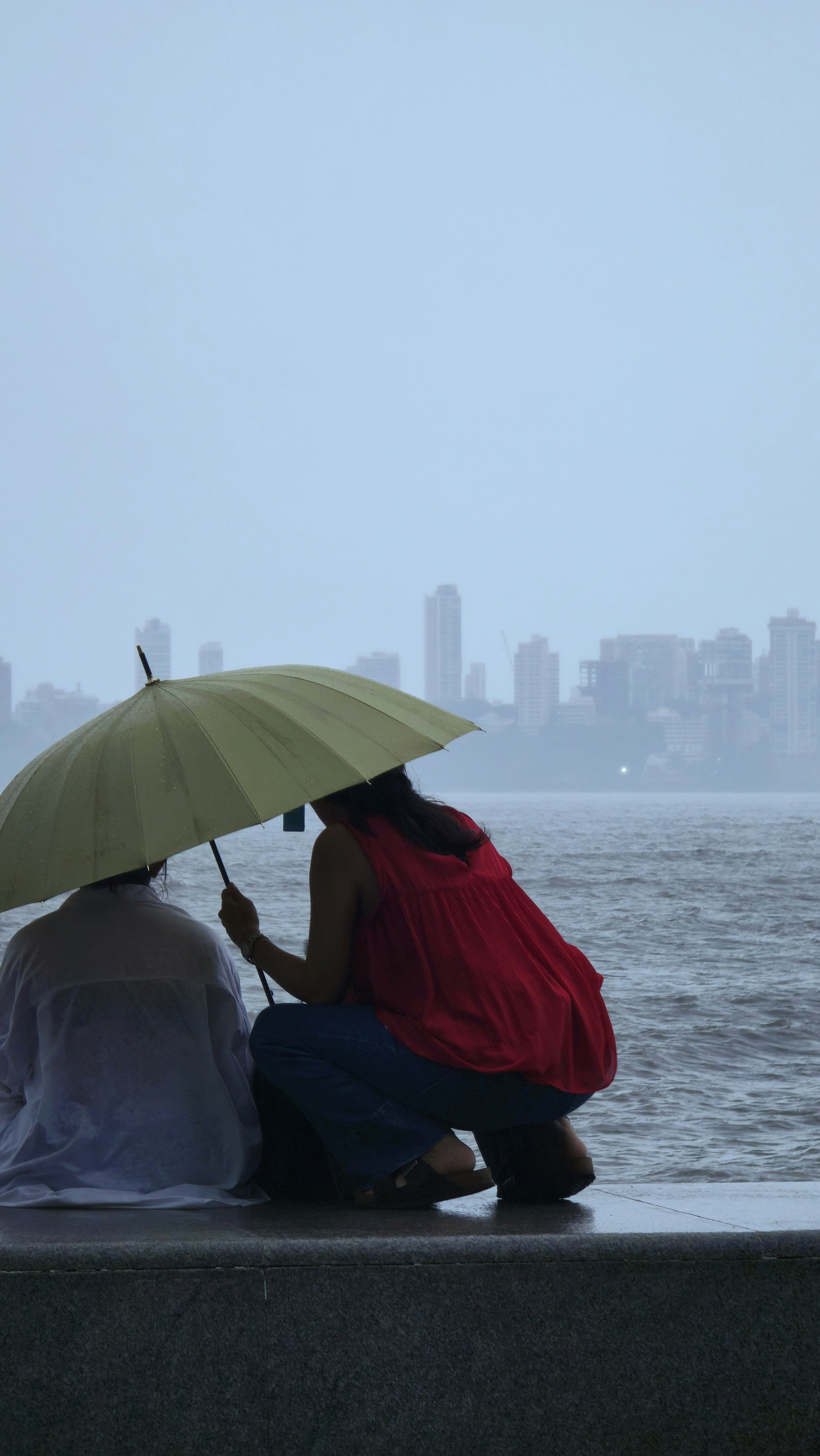 Two people sheltering under an umbrella by the water. photo – Free ...