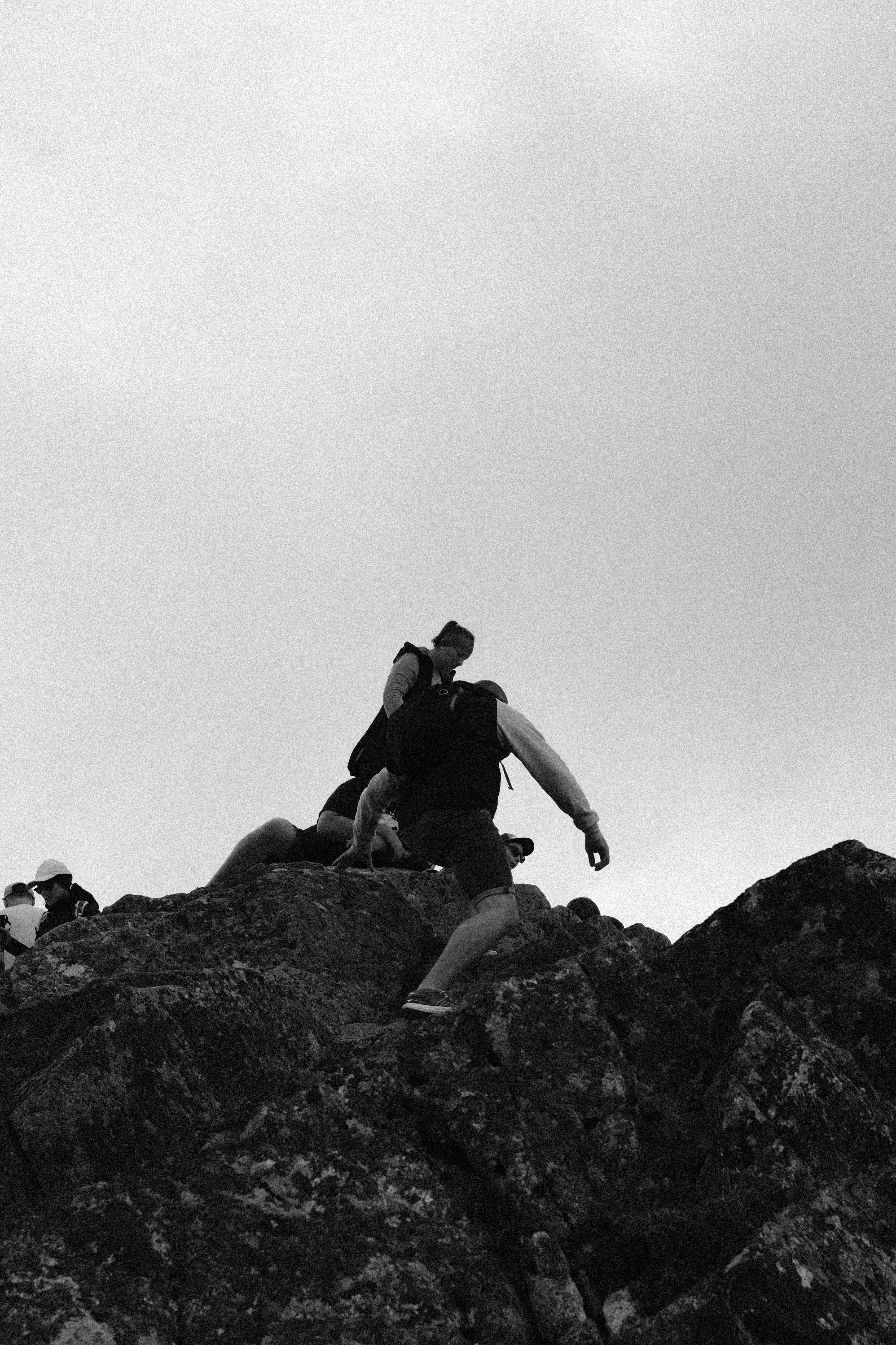 Hikers scramble up a rocky mountain.