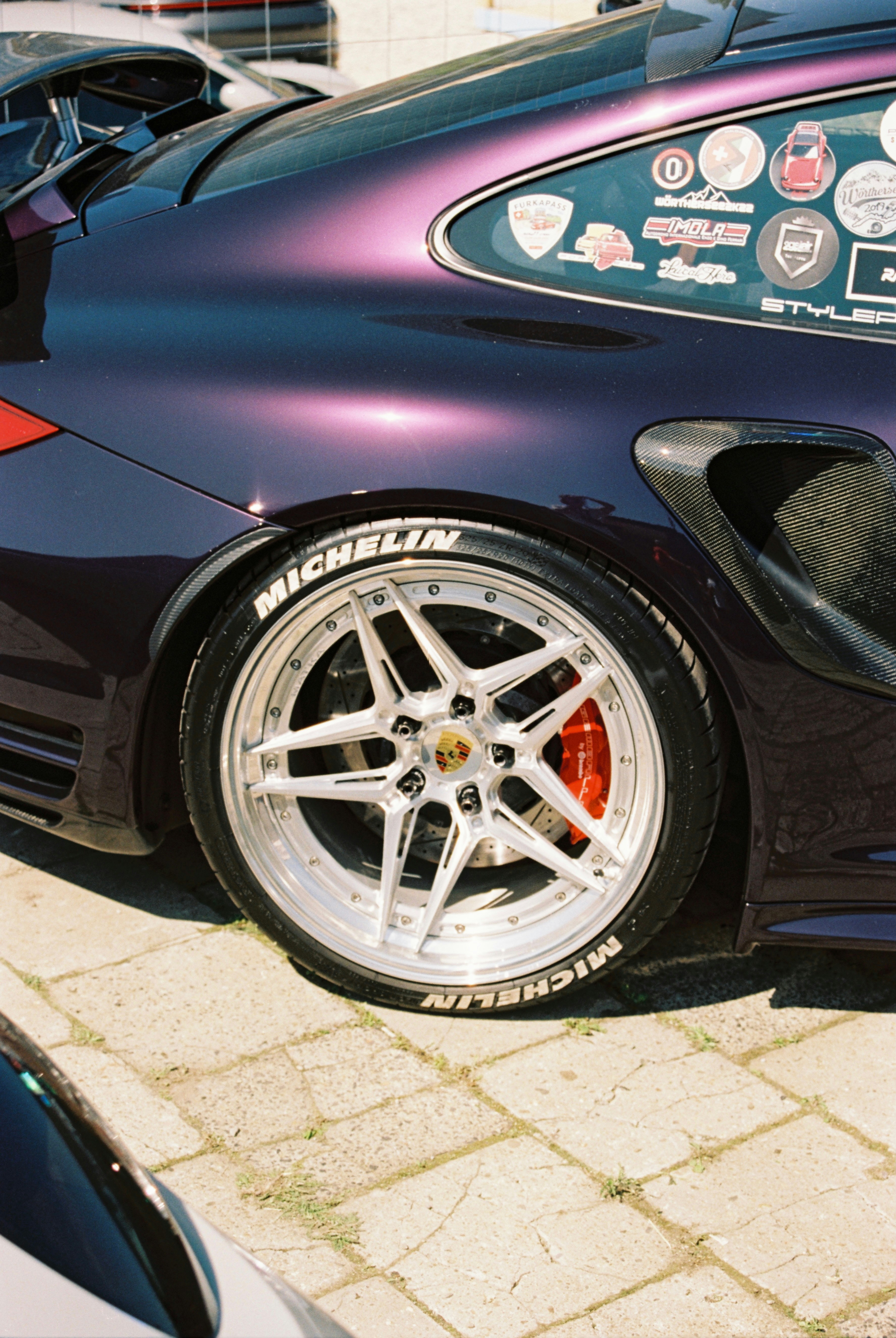 Close-up of a polished wheel and brake caliper on a modified sports car, showcasing intricate design and branding elements.
