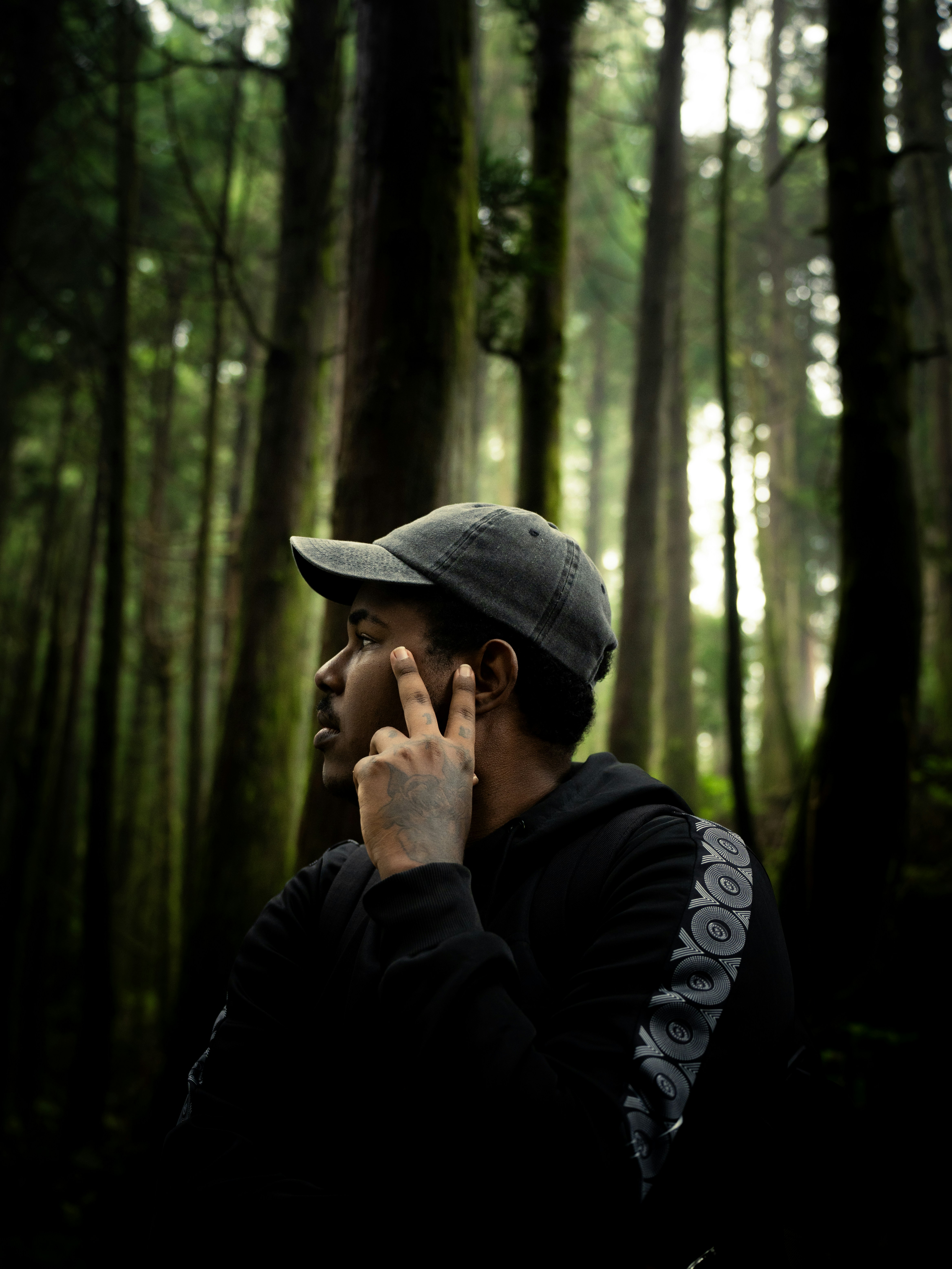 Garoto parado entre as arvores esperando por algo | A person stands in a moody, lush forest.