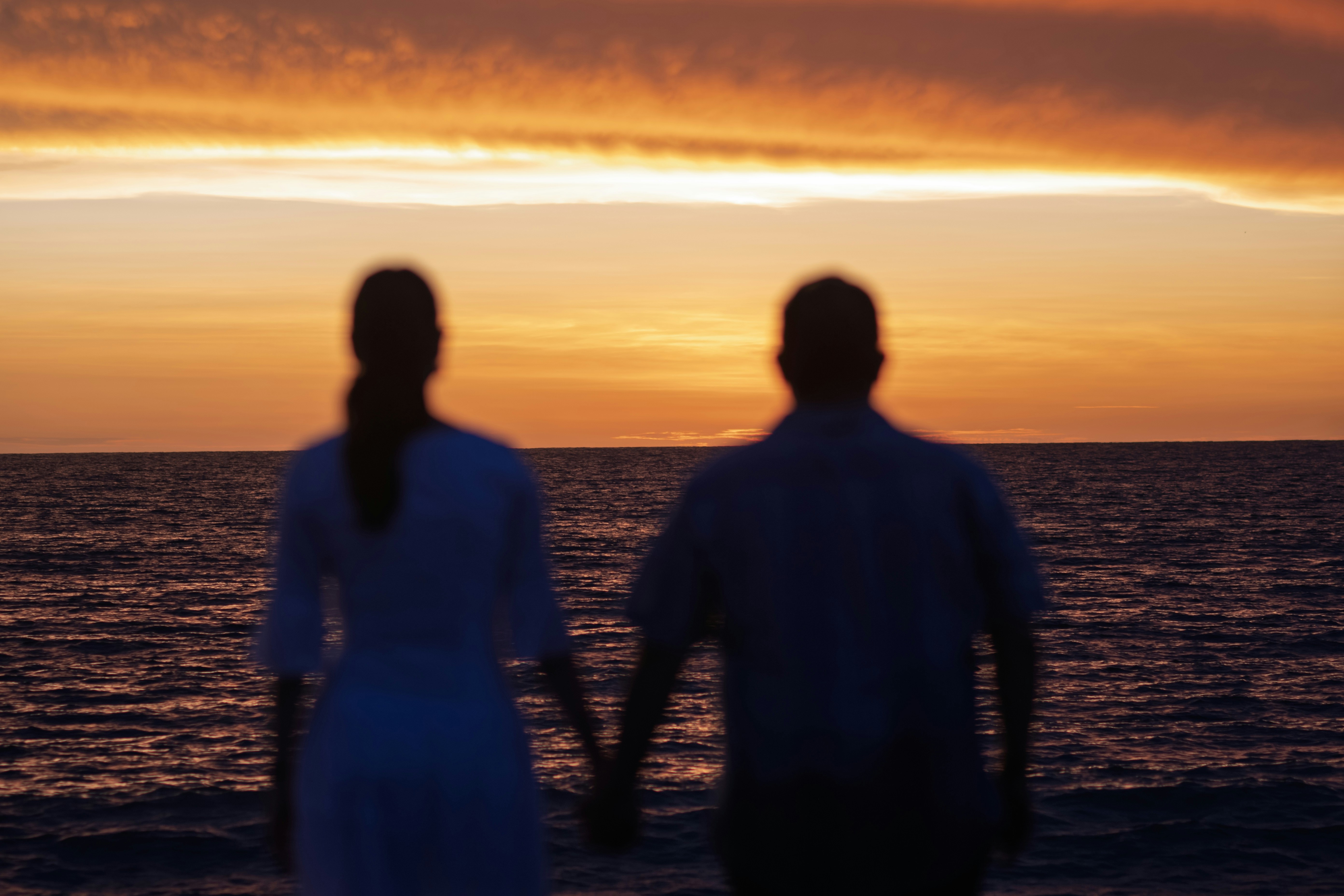 A couple holds hands while watching the sunset. photo – Free Woman ...