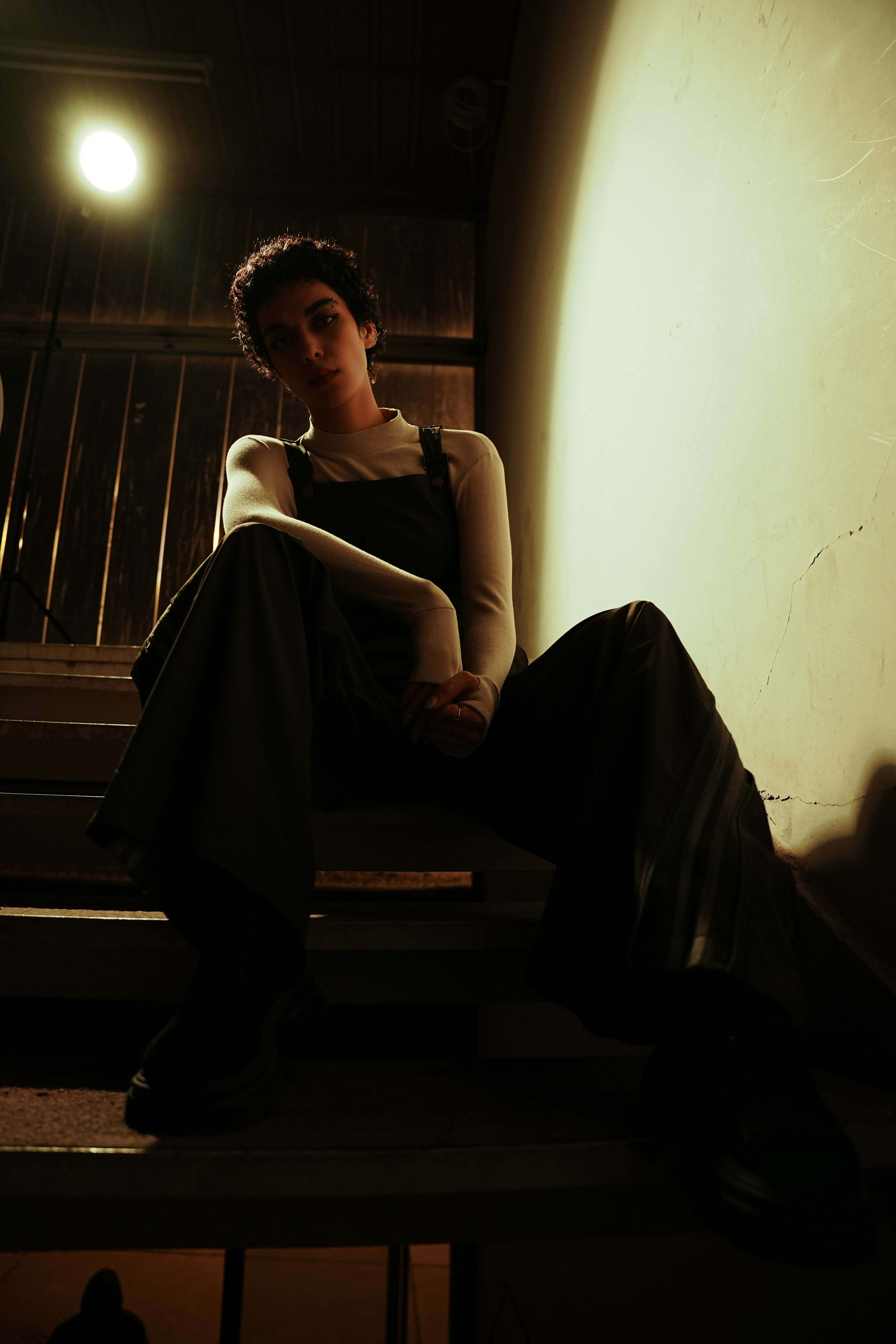 Une personne est assise dans les escaliers sous un éclairage dramatique ...