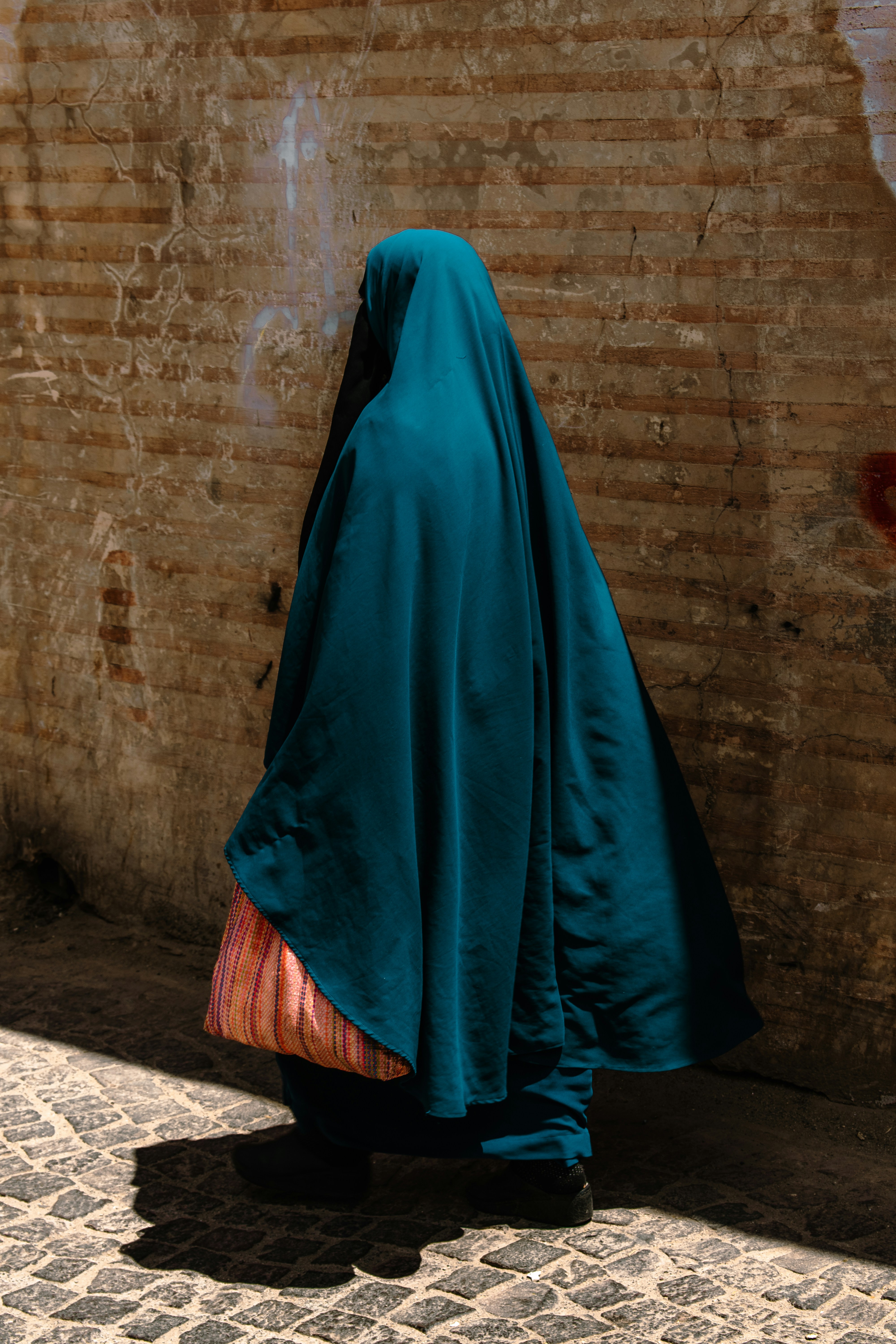 A woman walks down a street in a burqa.
