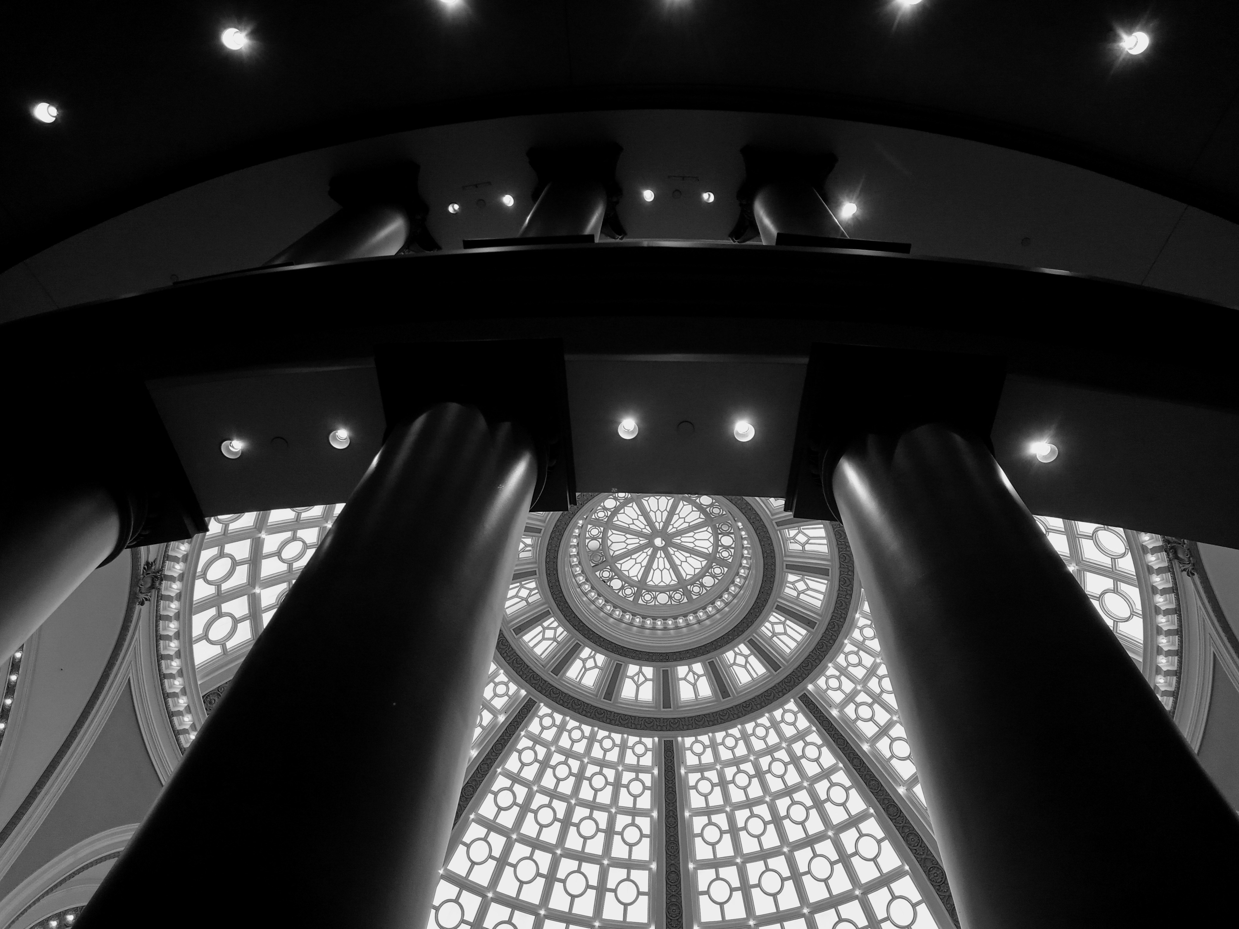 Intricate ceiling design viewed from below, framed by towering columns and illuminated by soft overhead lights.