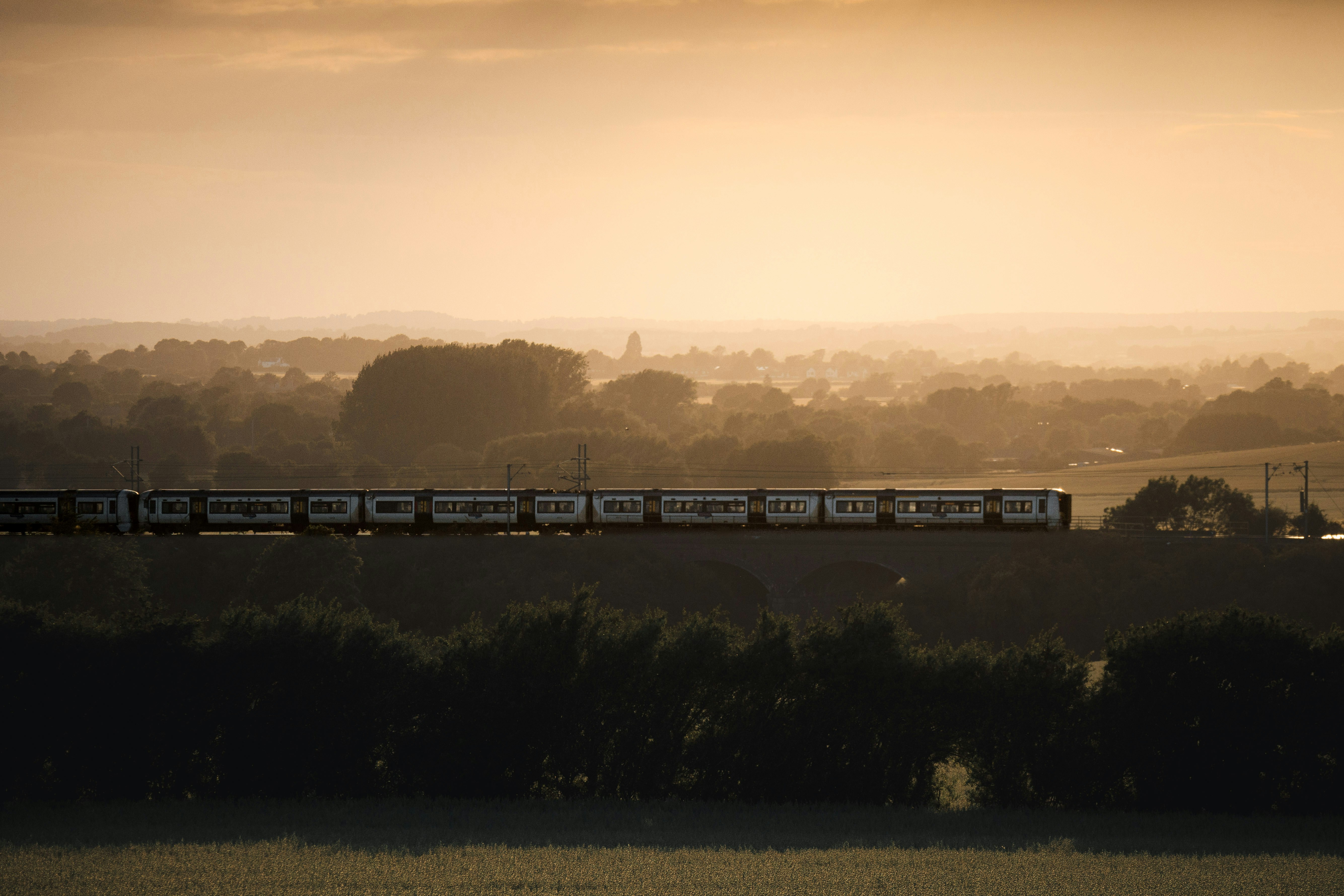A train crosses a bridge at sunset in rural Hertfordshire | A train moves through a misty, golden landscape.
