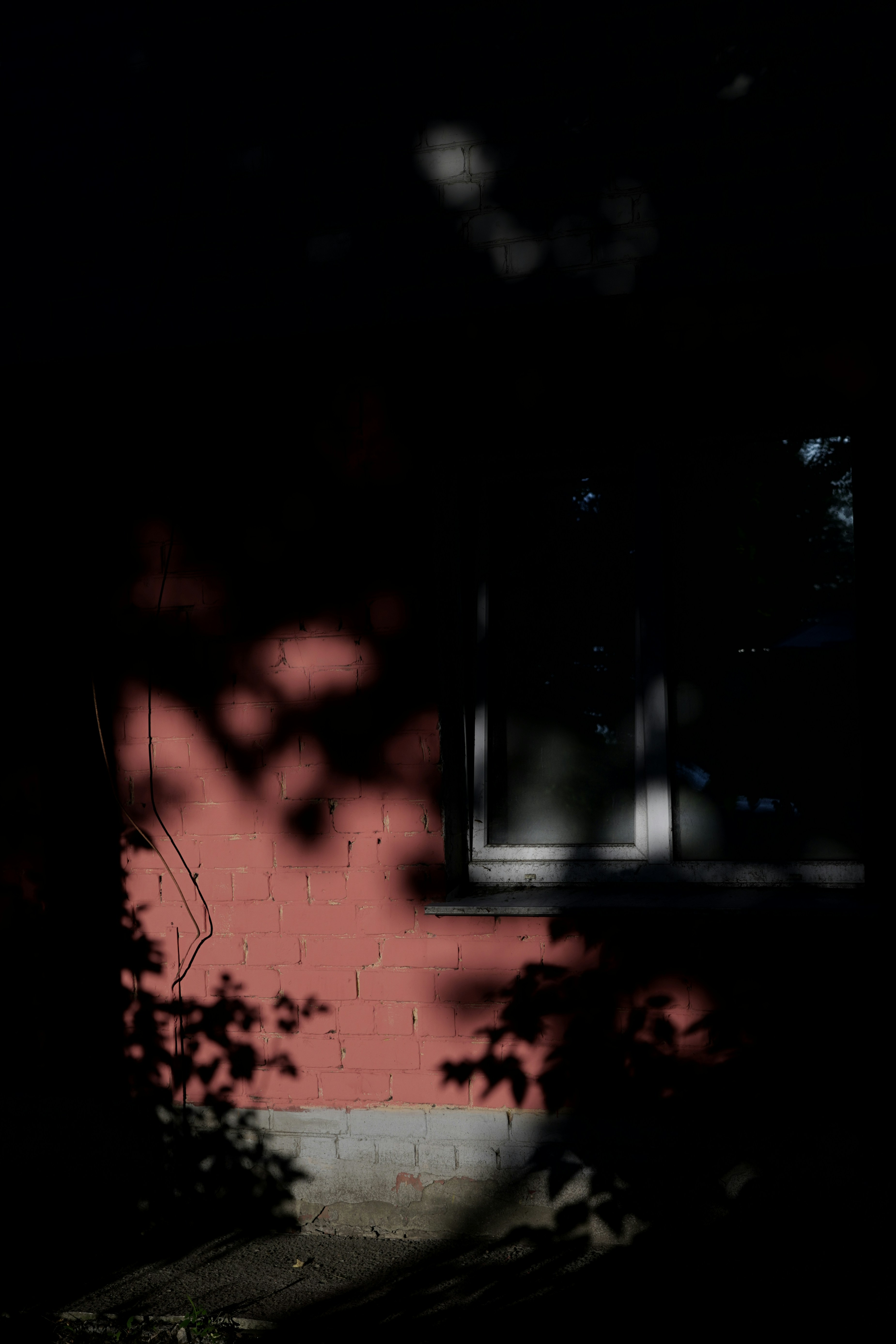 Shadows fall on a red brick wall.