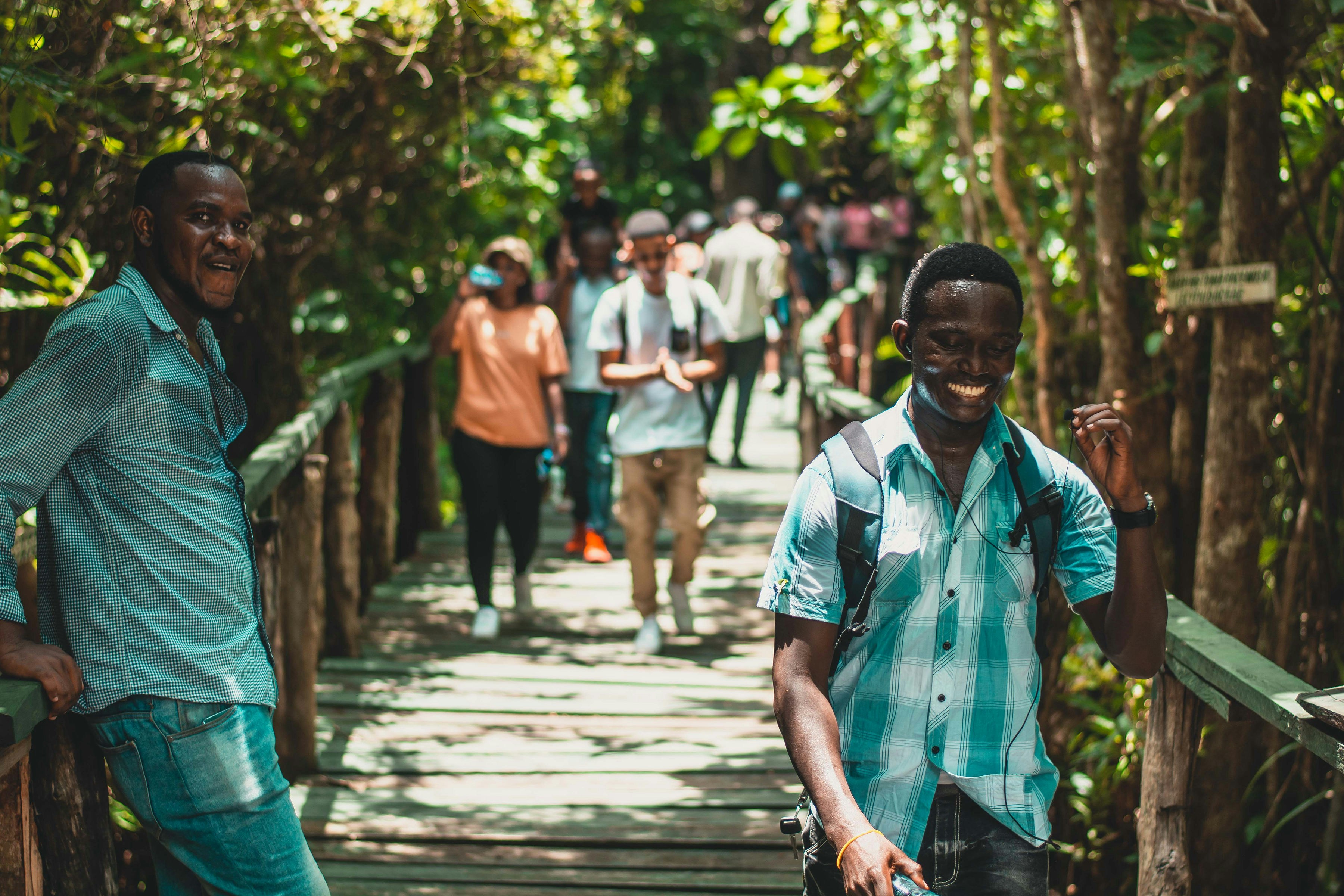 People are walking on a wooden bridge in nature.
