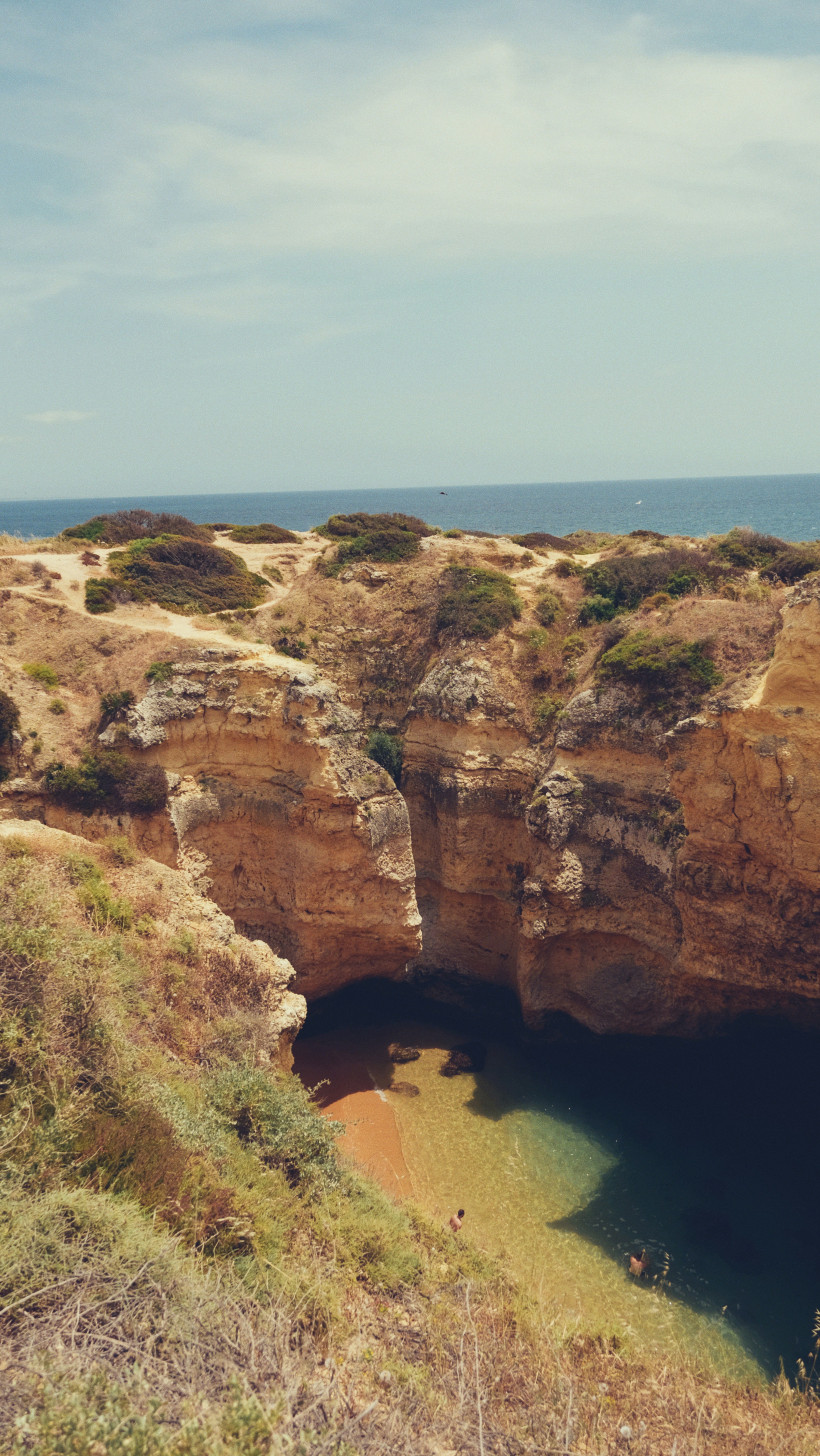 Secluded cove with turquoise waters surrounded by rugged cliffs and lush greenery, inviting exploration and tranquility.