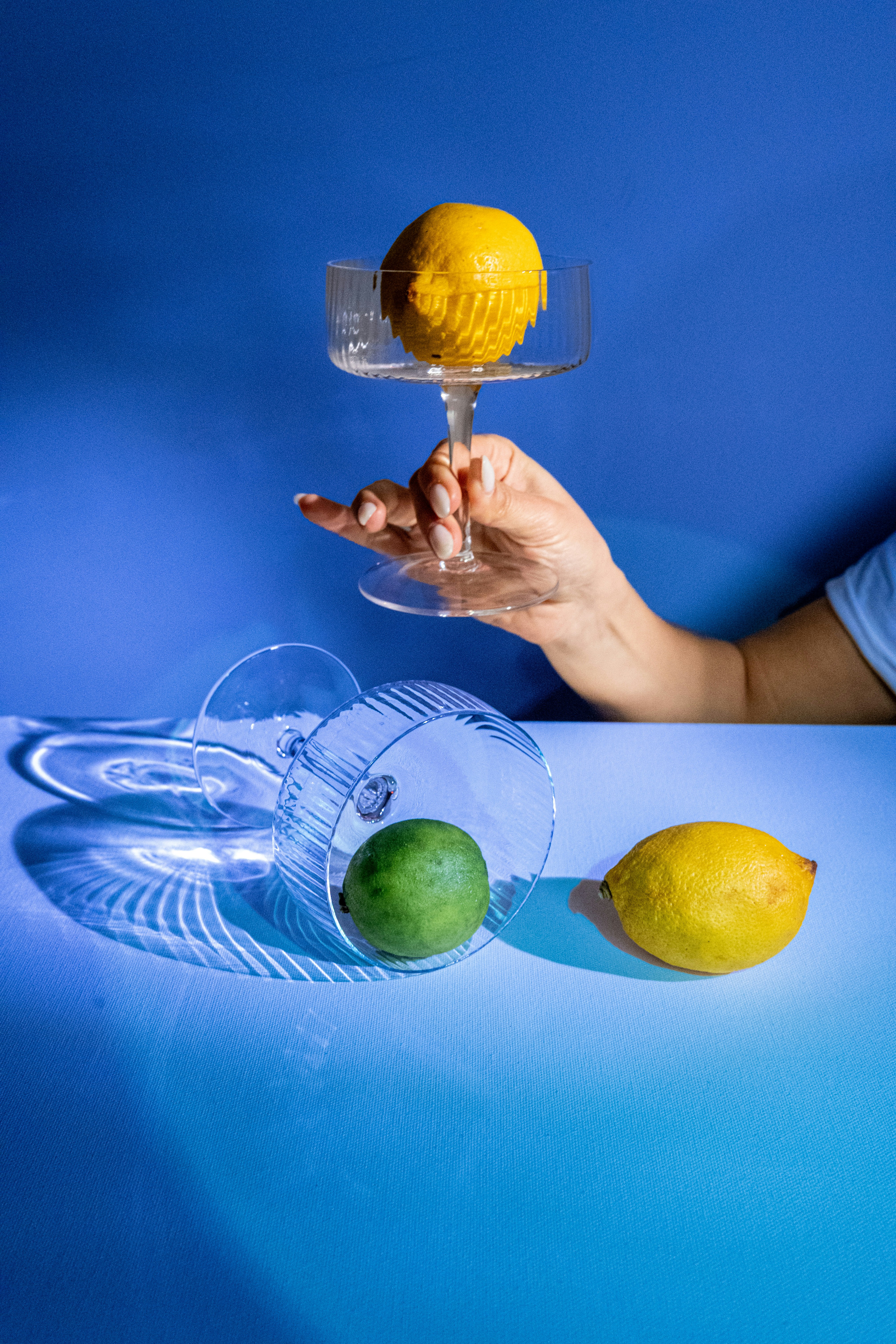 A hand holds a glass with a lemon.
