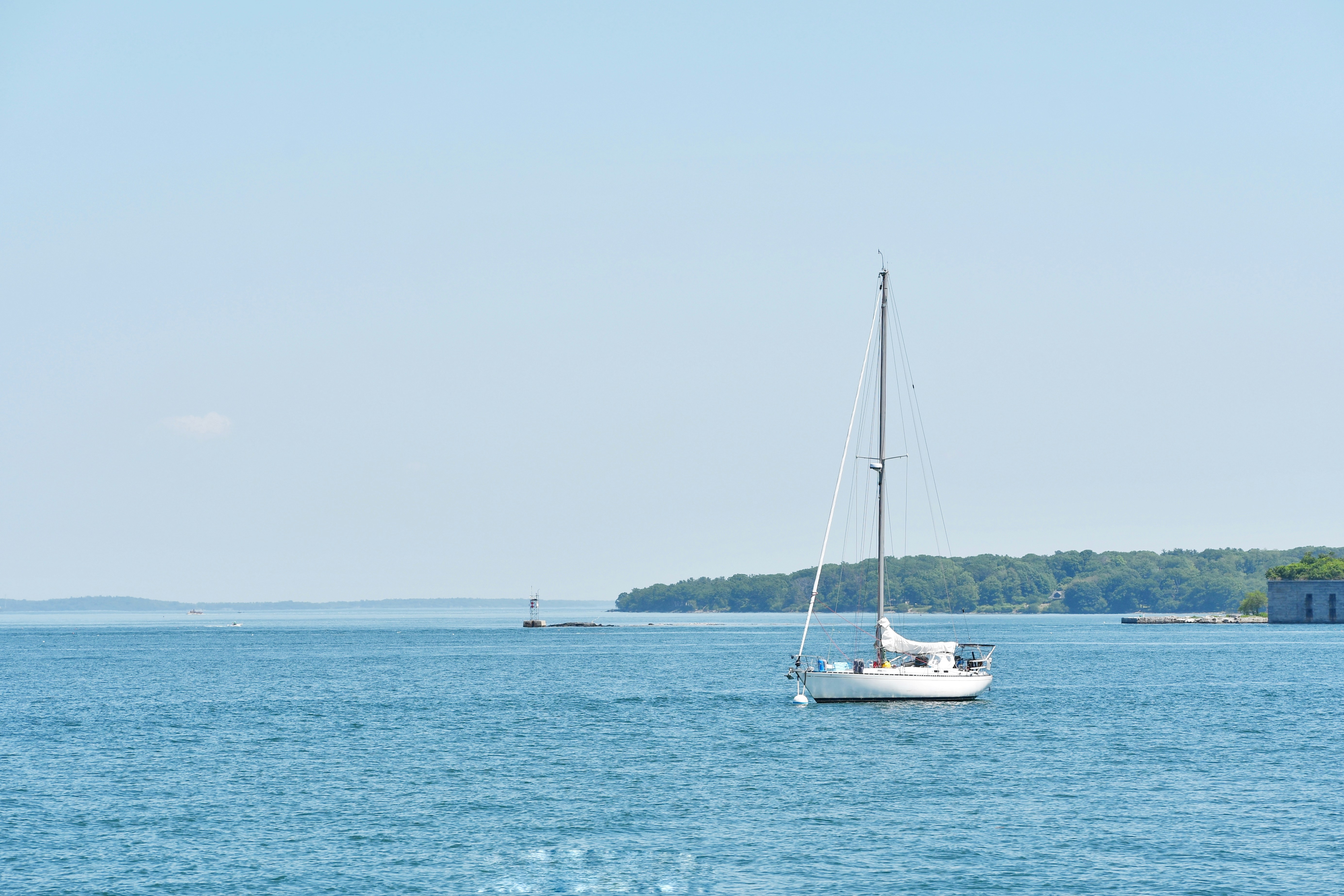Boats sailing on the water in Maine | A sailboat floats in the calm blue ocean.