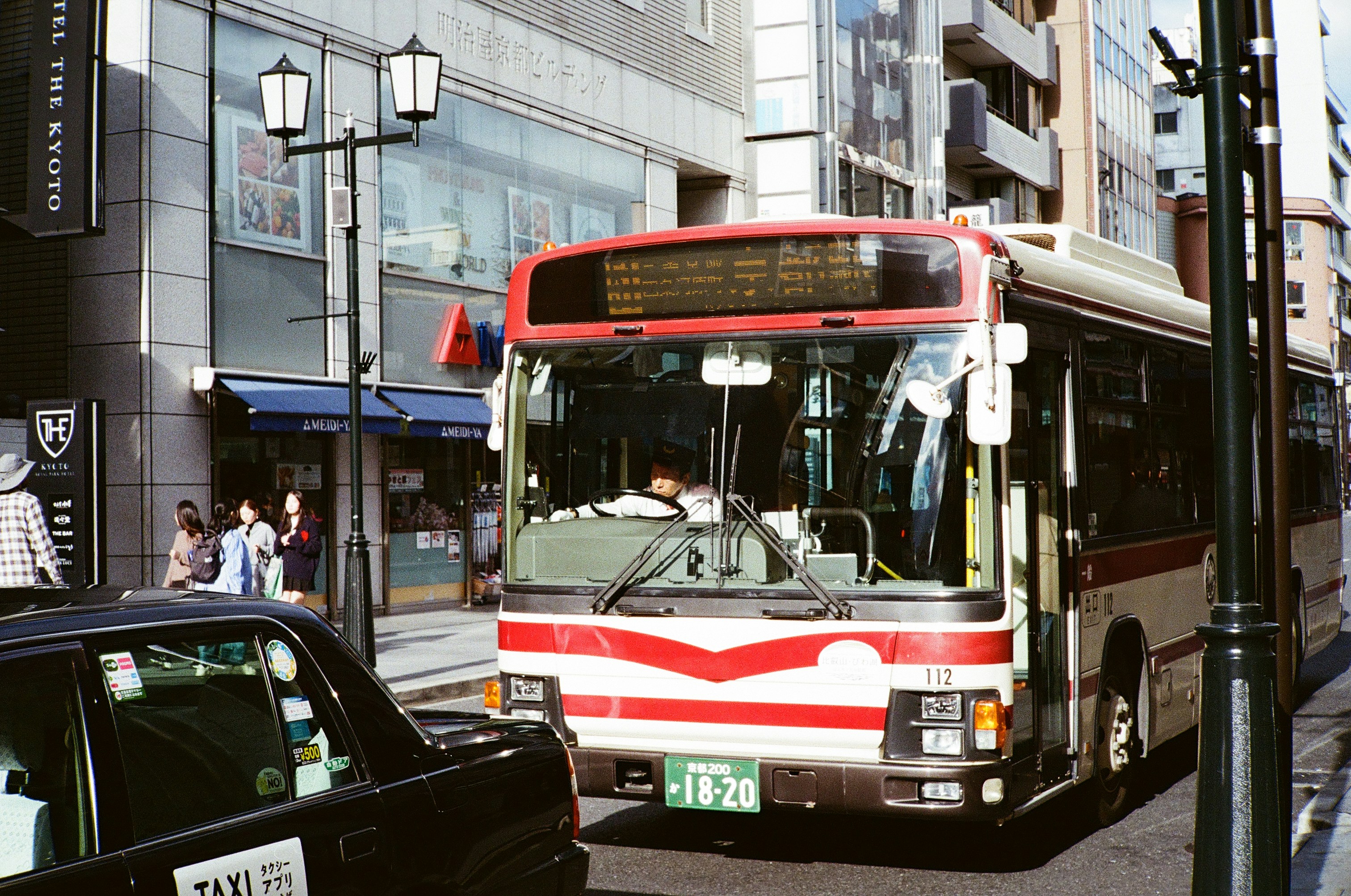 A bus is driving down a busy city street. photo – Free Street Image on ...