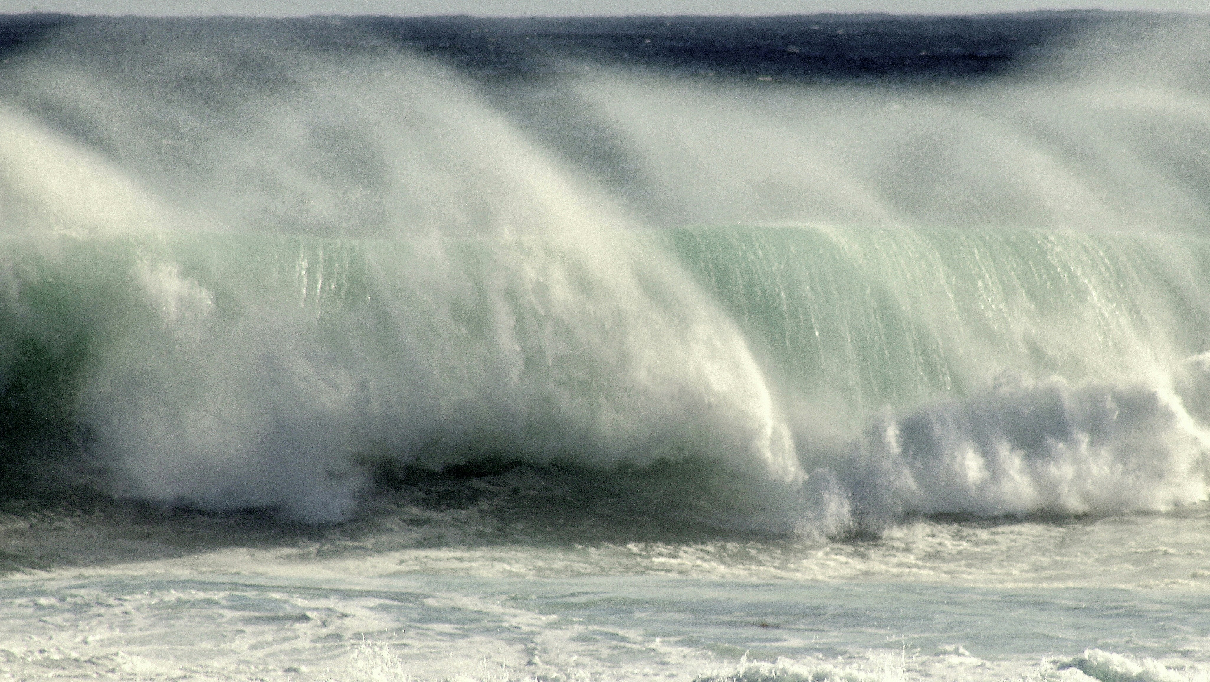 Powerful waves crashing against the shore, capturing the raw energy of the sea. The frothy spray creates a dynamic interplay of water and light.