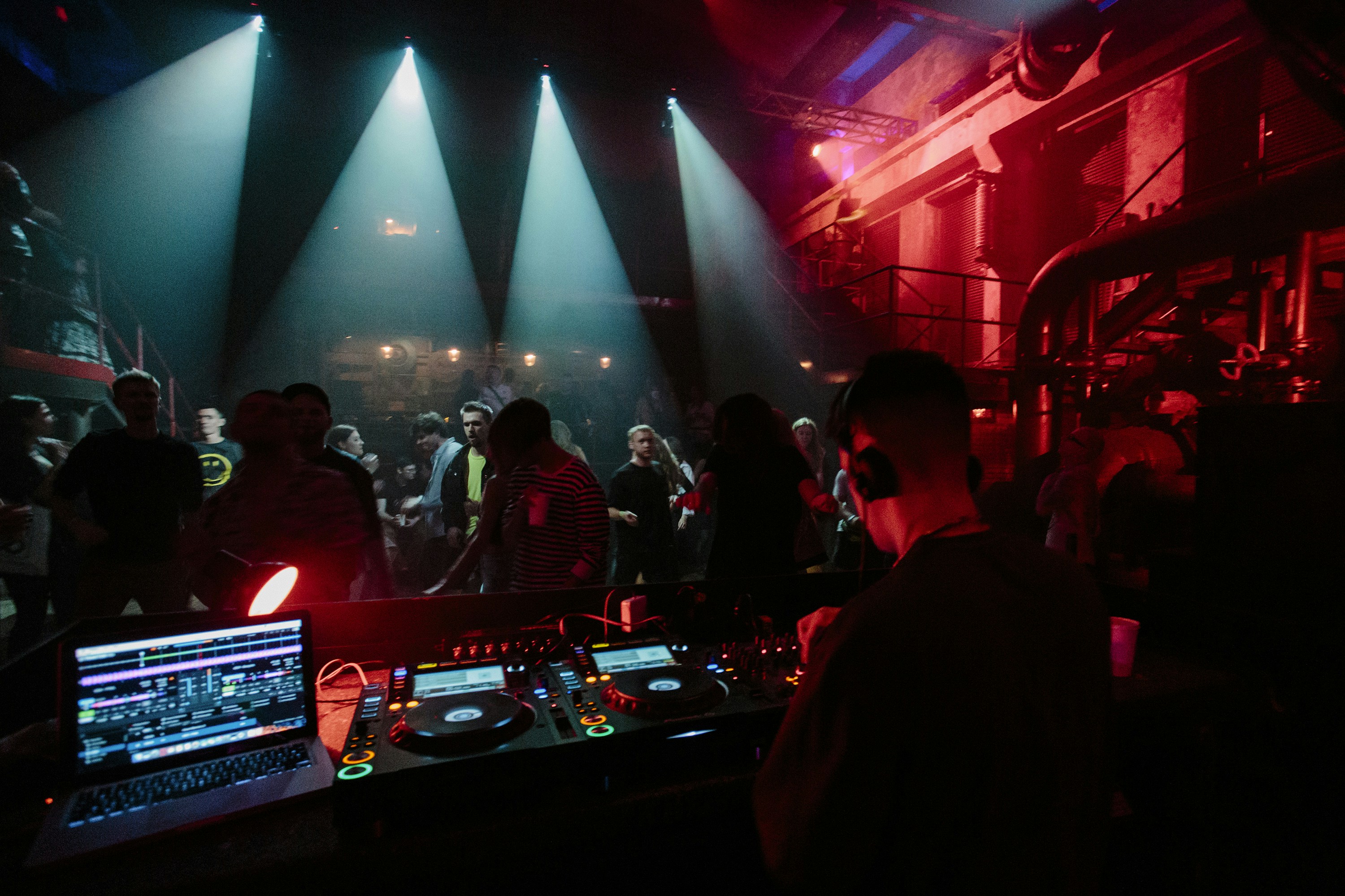 A dj plays music in a crowded nightclub.
