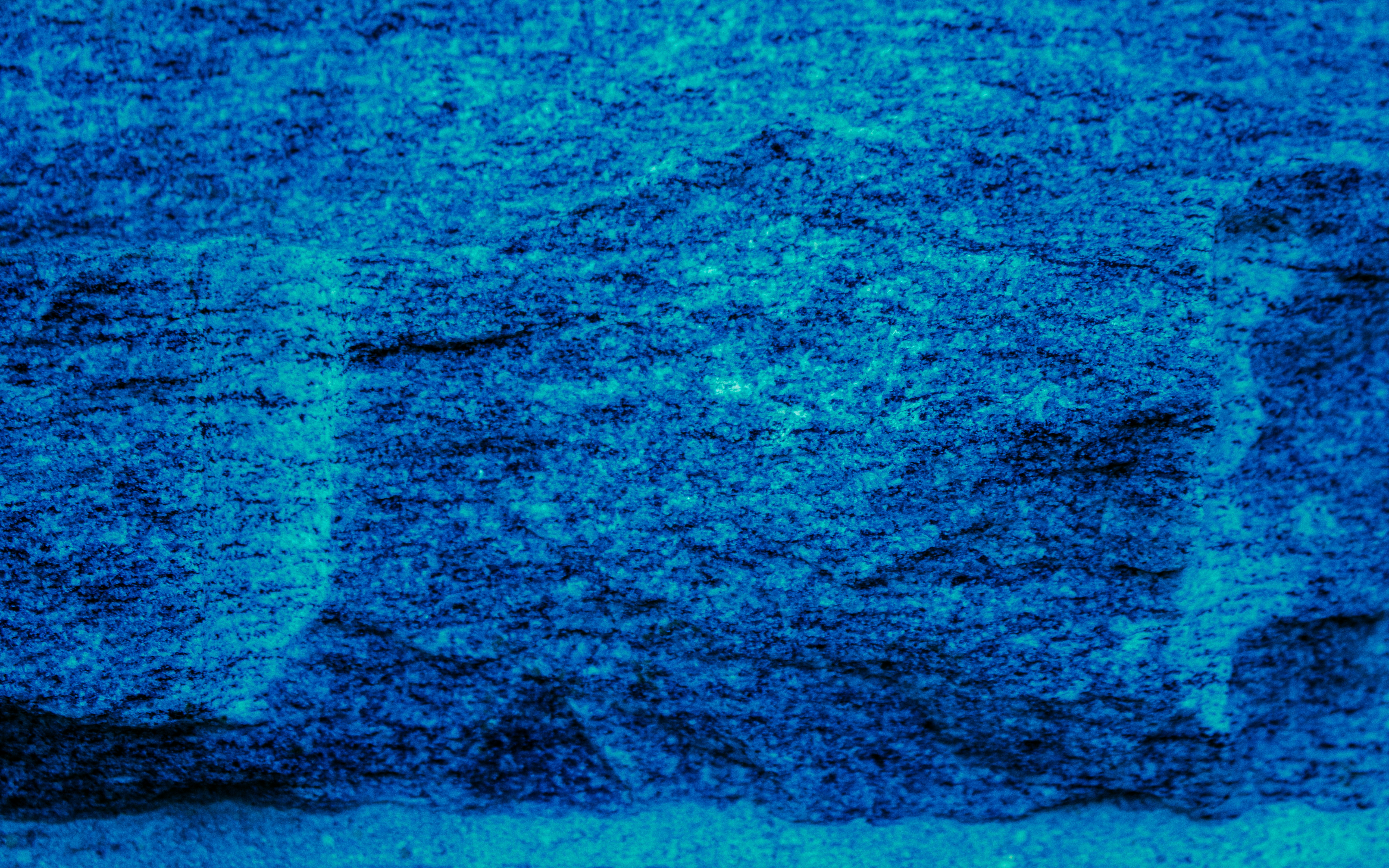 Abstract texture resembling underwater rock formations illuminated in deep blue hues.