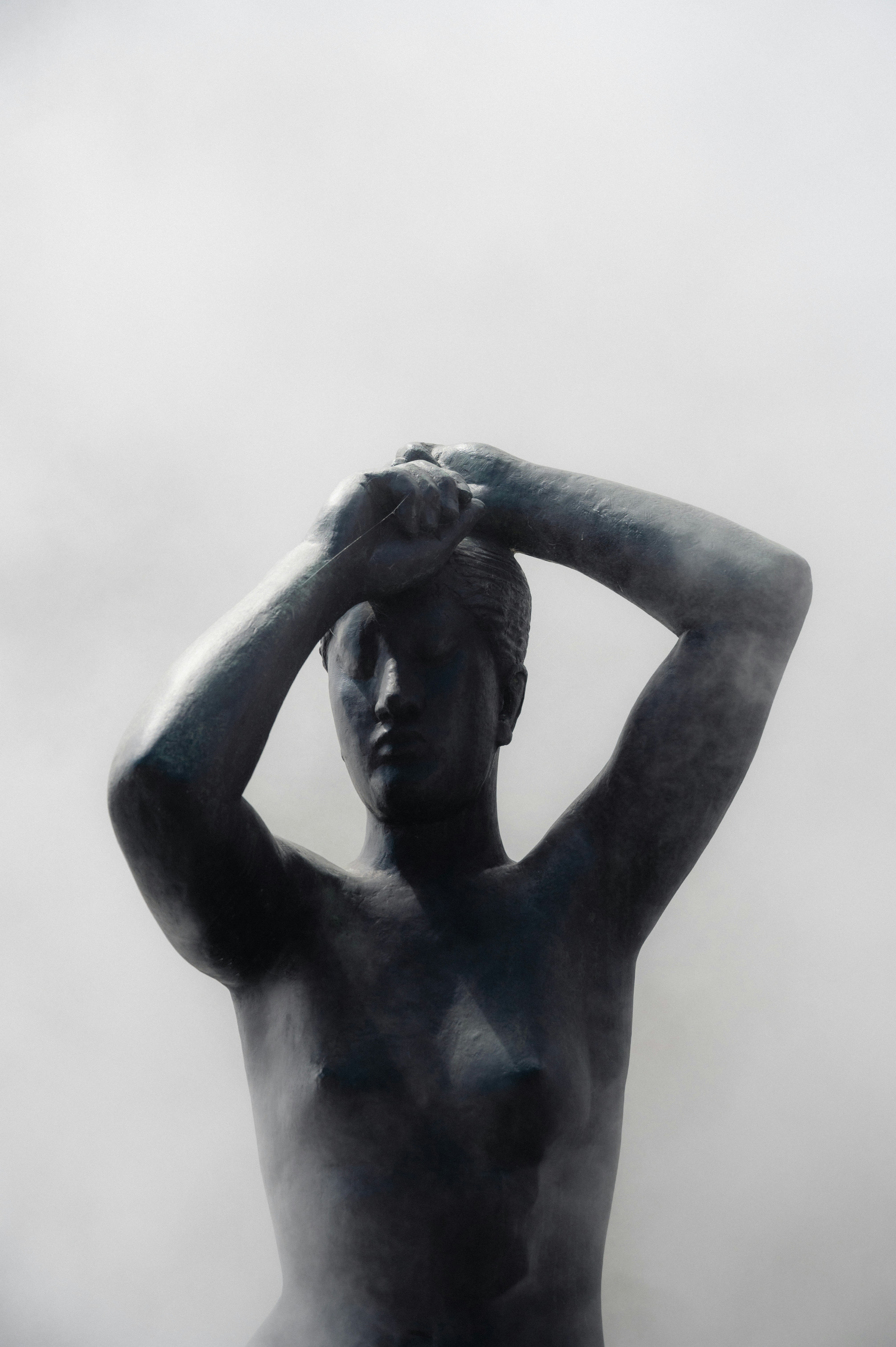 A statue of a woman poses with arms raised.