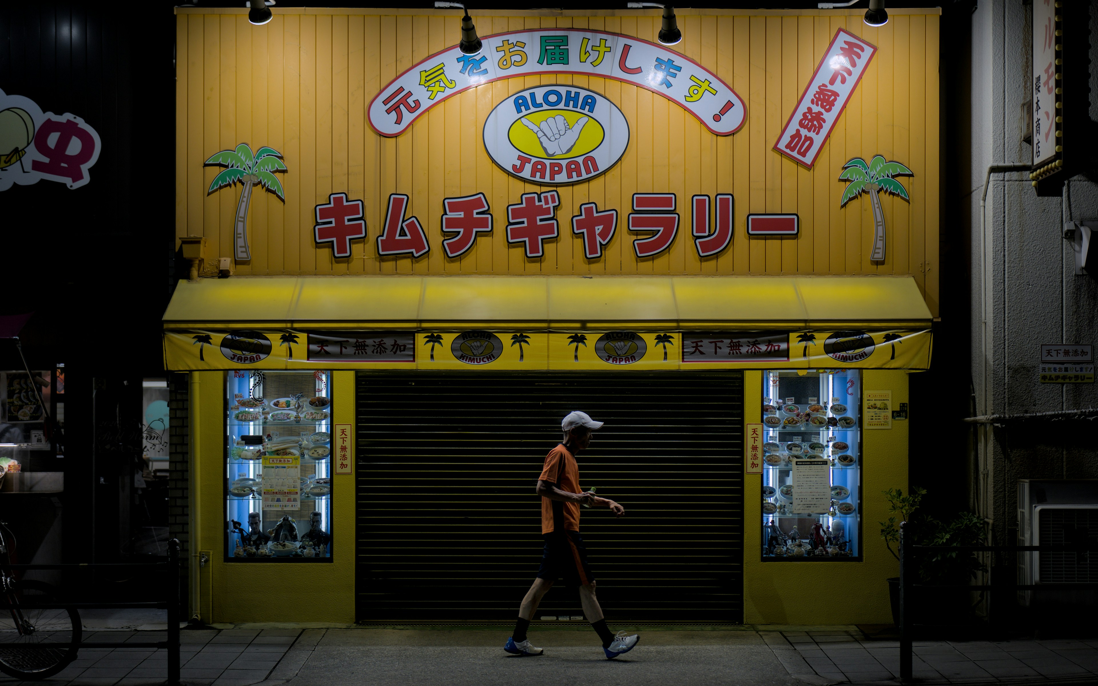 A person walks past a brightly lit japanese storefront. photo – Free ...