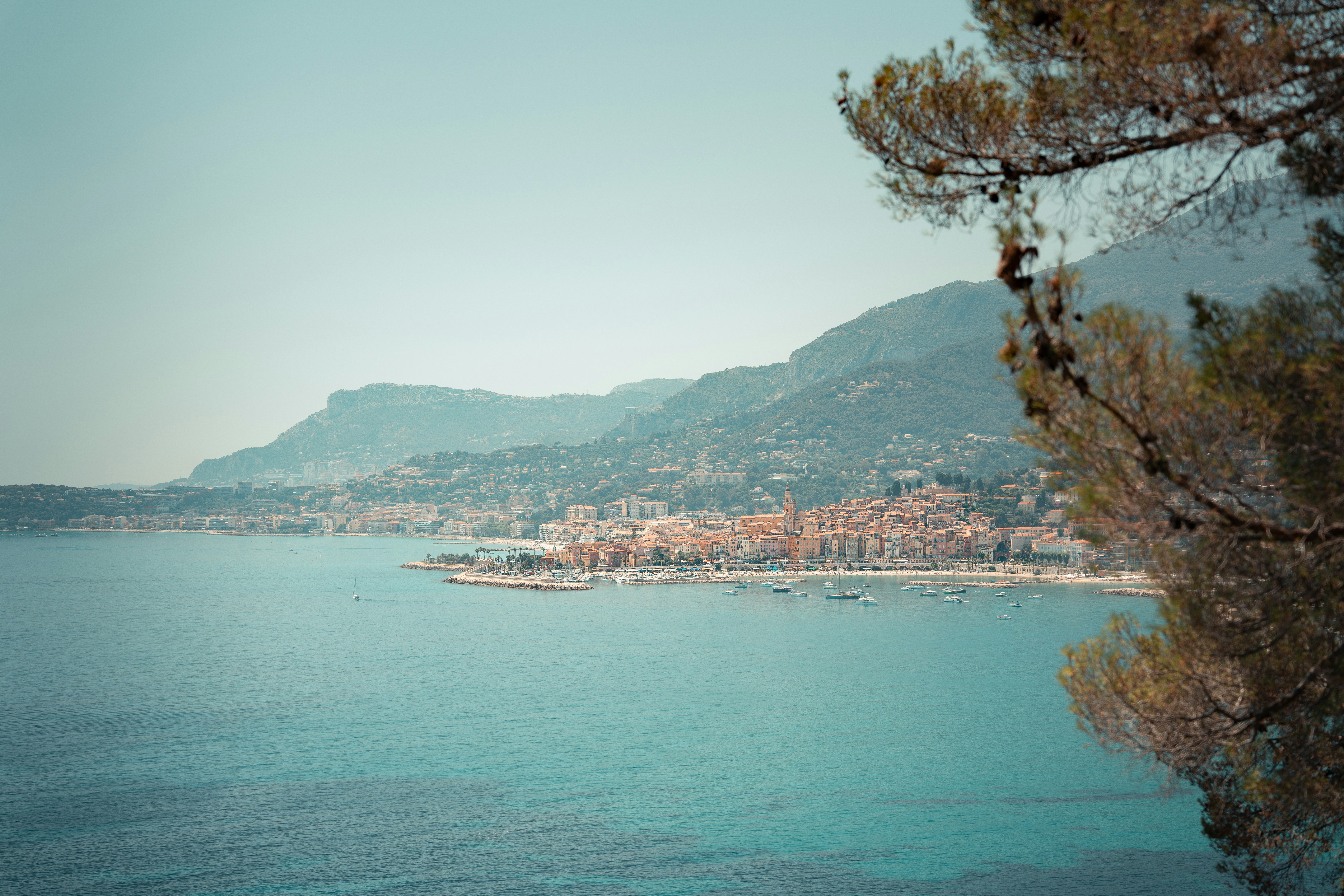 Coastal town nestled by turquoise water and mountains.